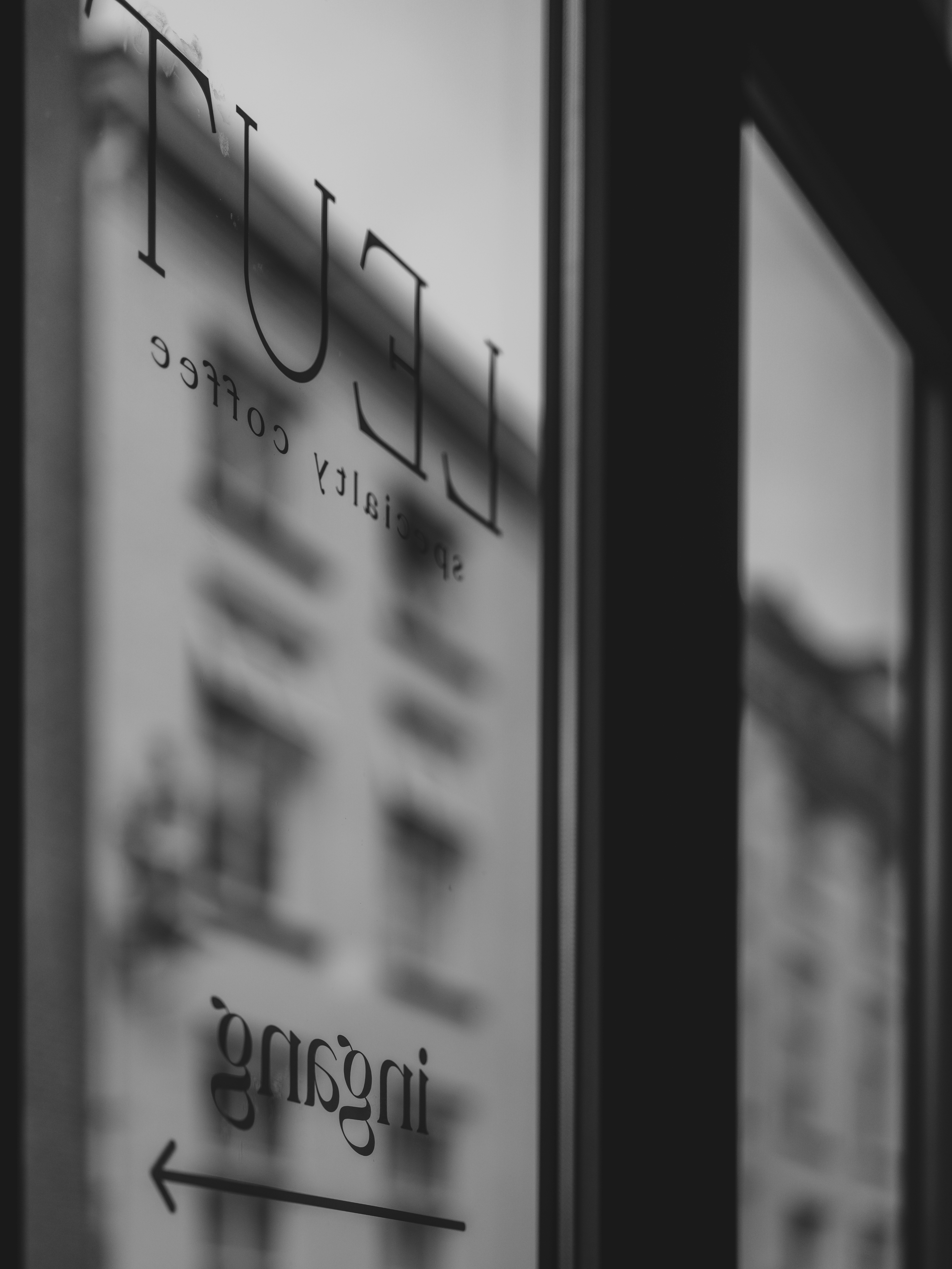 Reflections on a Glass Door: A Quiet Boutique Window in Monochrome