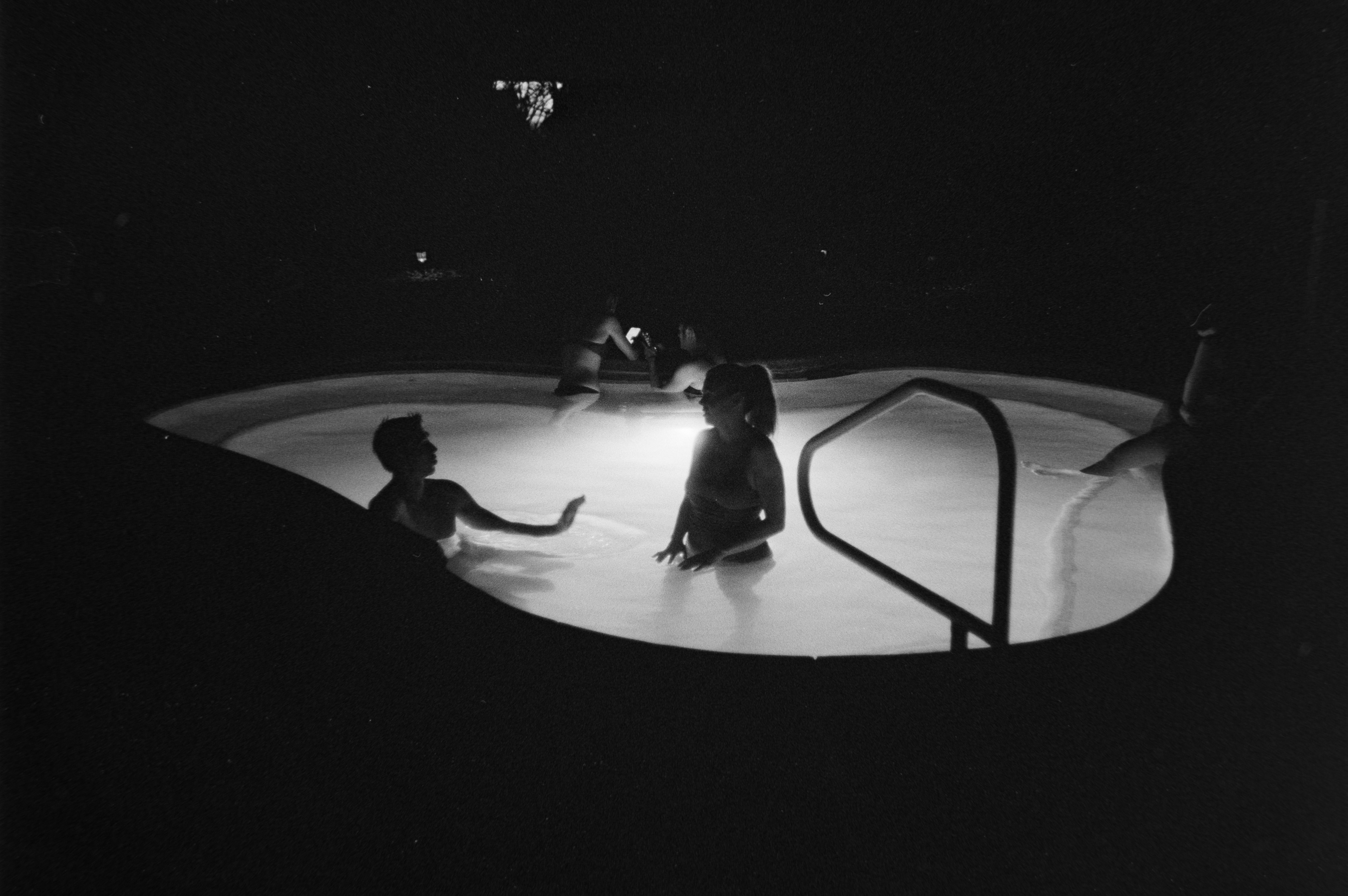 Night Swim: Figures in a Pool Under Soft Glow