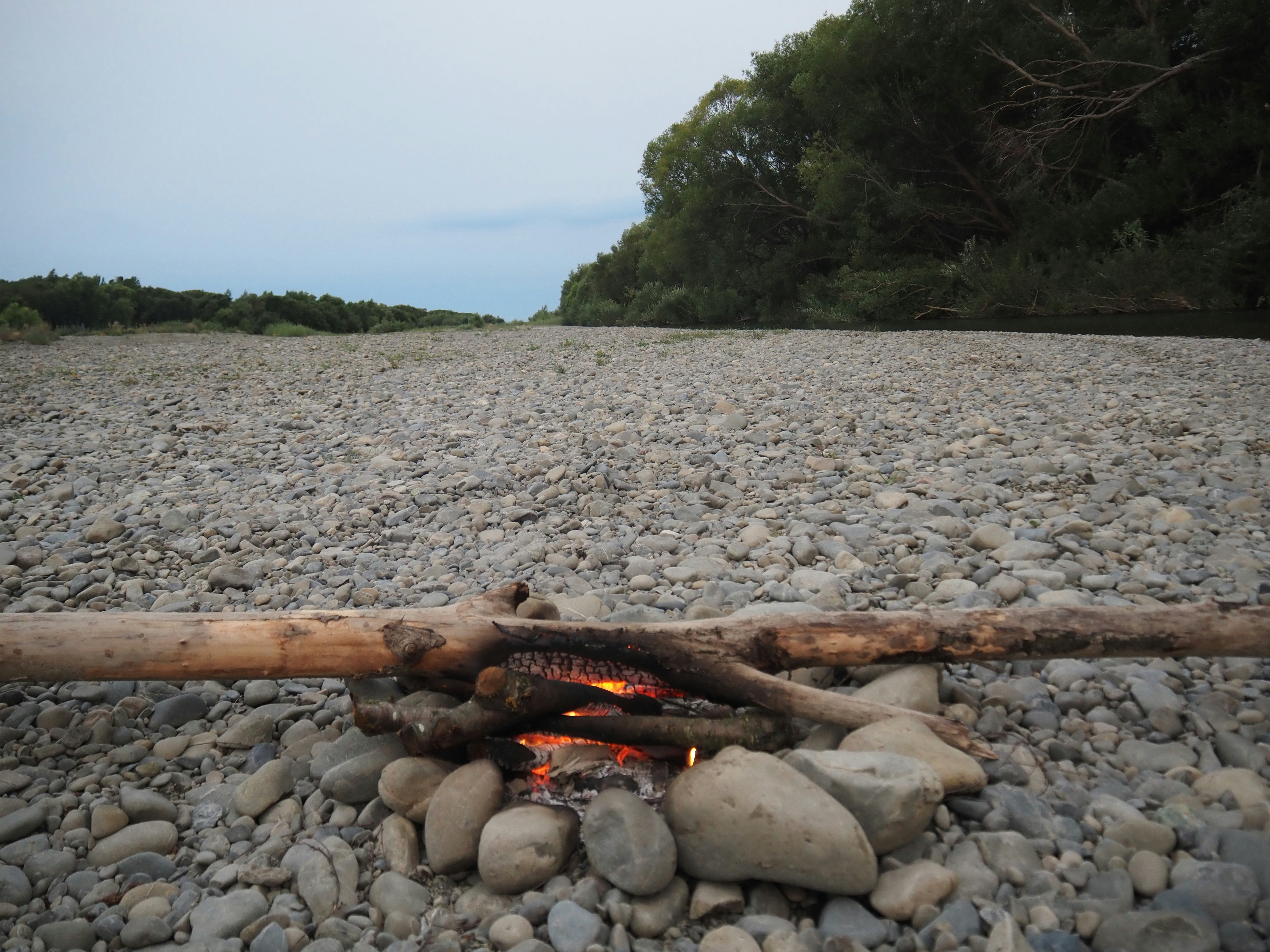 Pebble Backdrop Campfire on a Quiet Riverbank