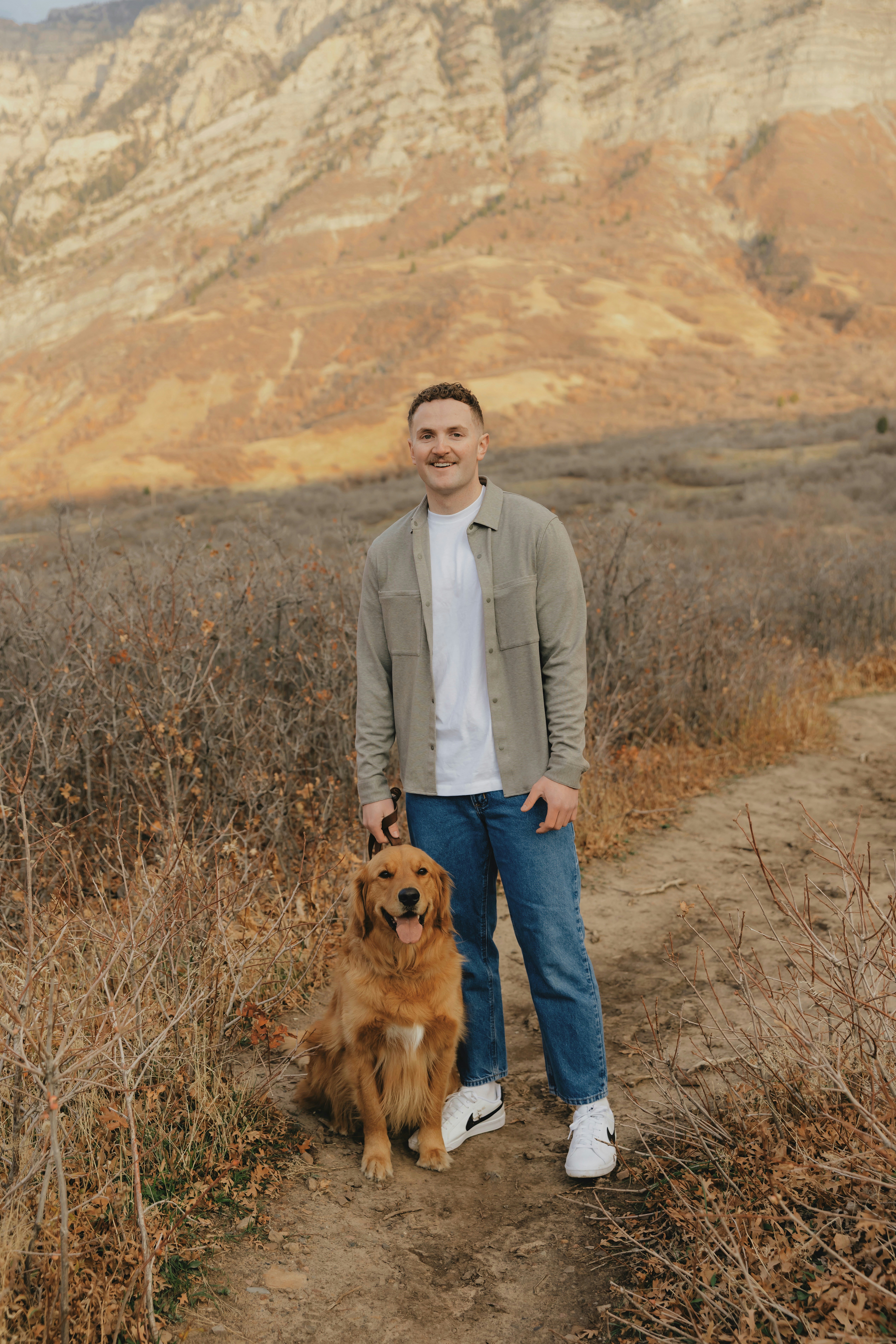 Smiling Man with Golden Retriever in a Mesa-Backed Landscape