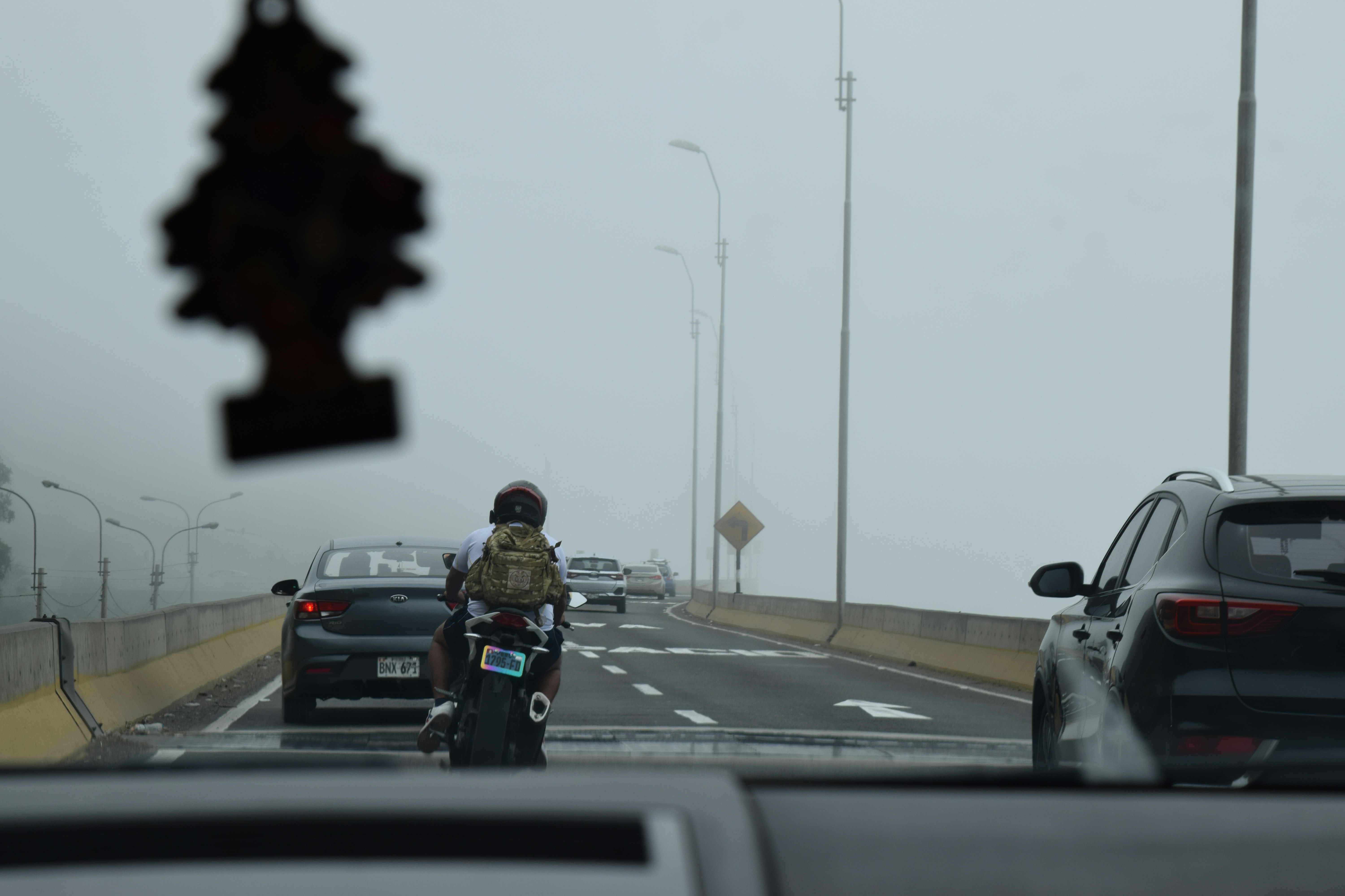 Mid‑Lane Ascent: Motorcycle Rider Surging Through a Car‑Heavy Bridge