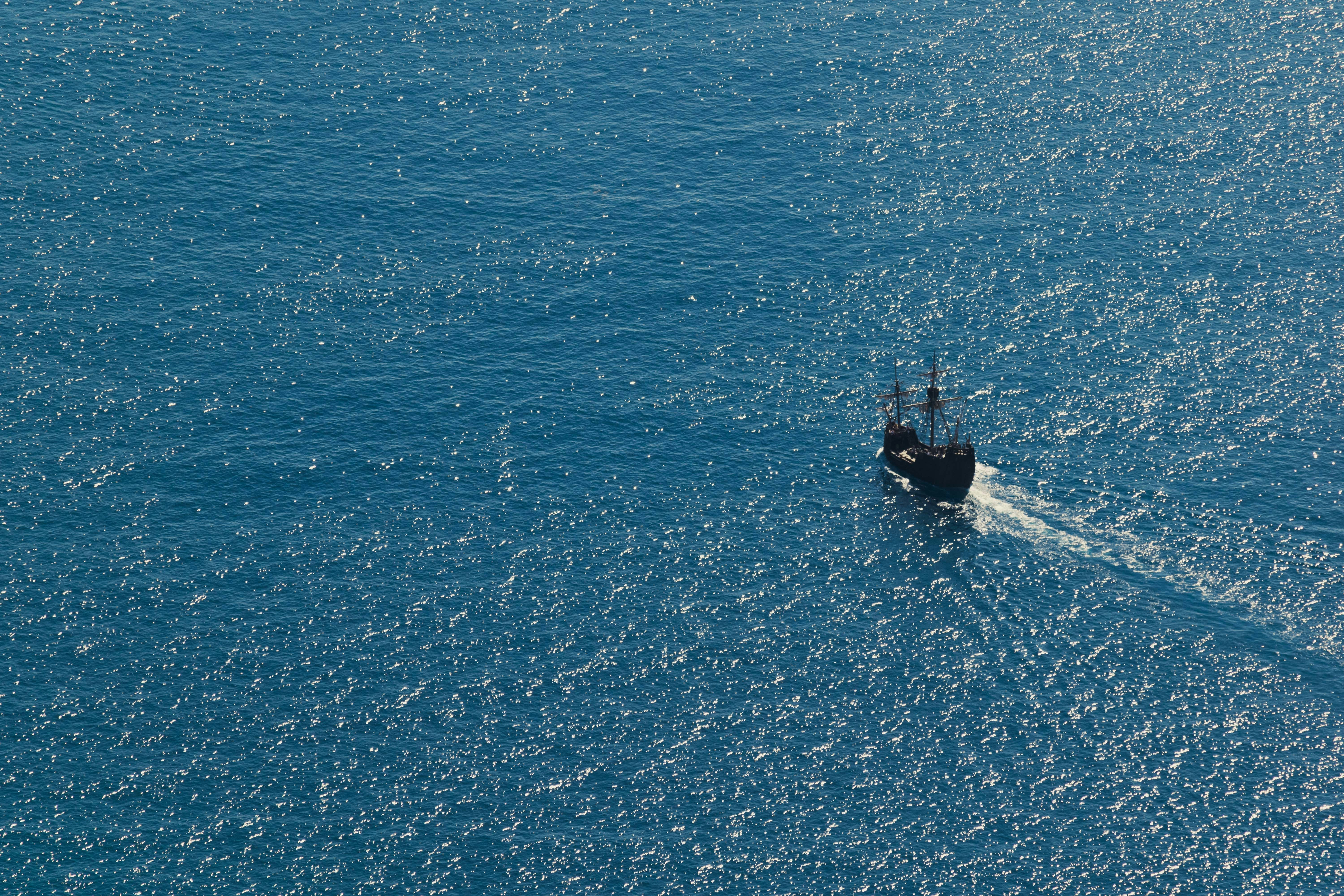 A Lone Vessel Arcs Through Sparkling Blue Wake