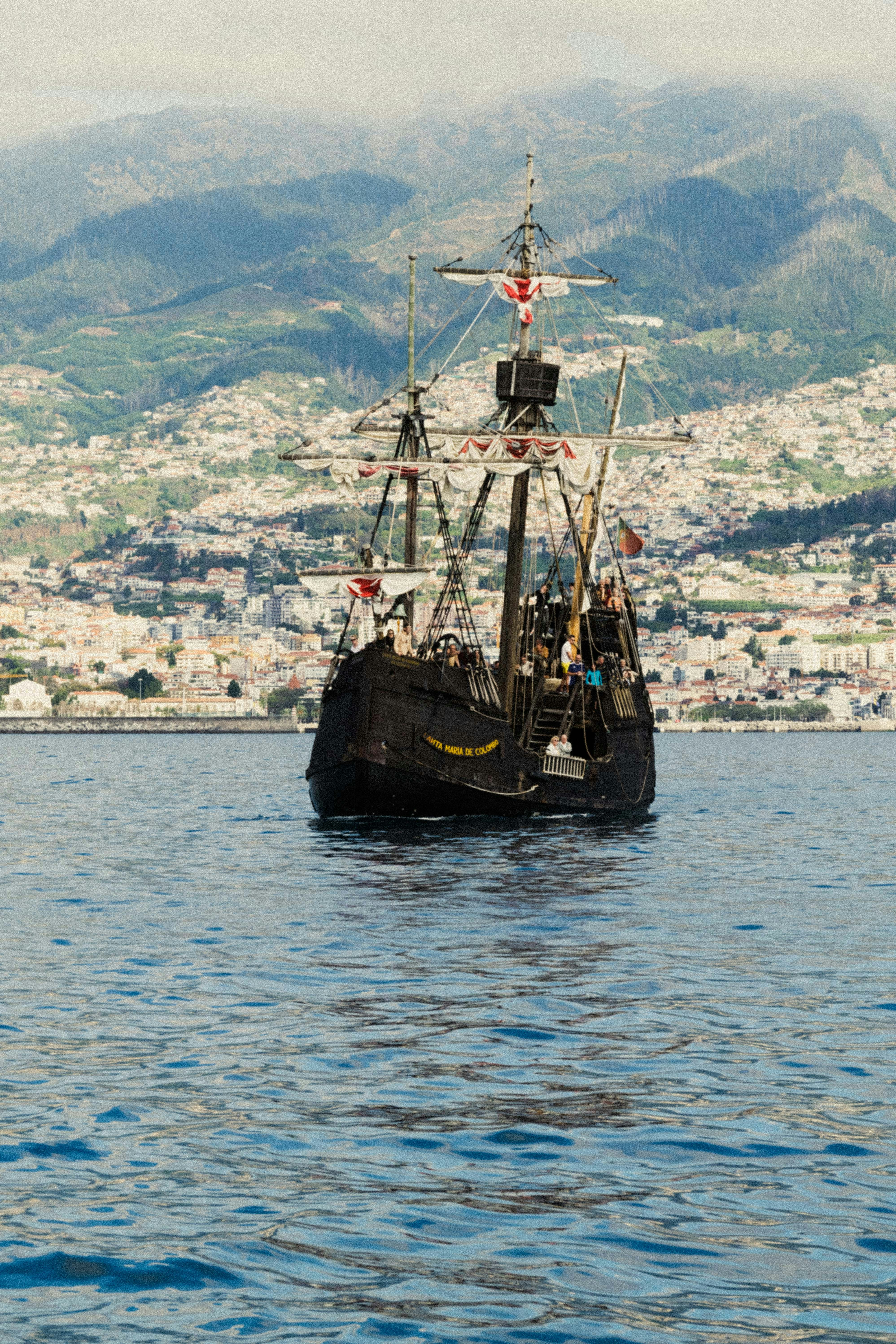 Black Flag on the Blue Sea: A Historic Galleon against a Coastal Town