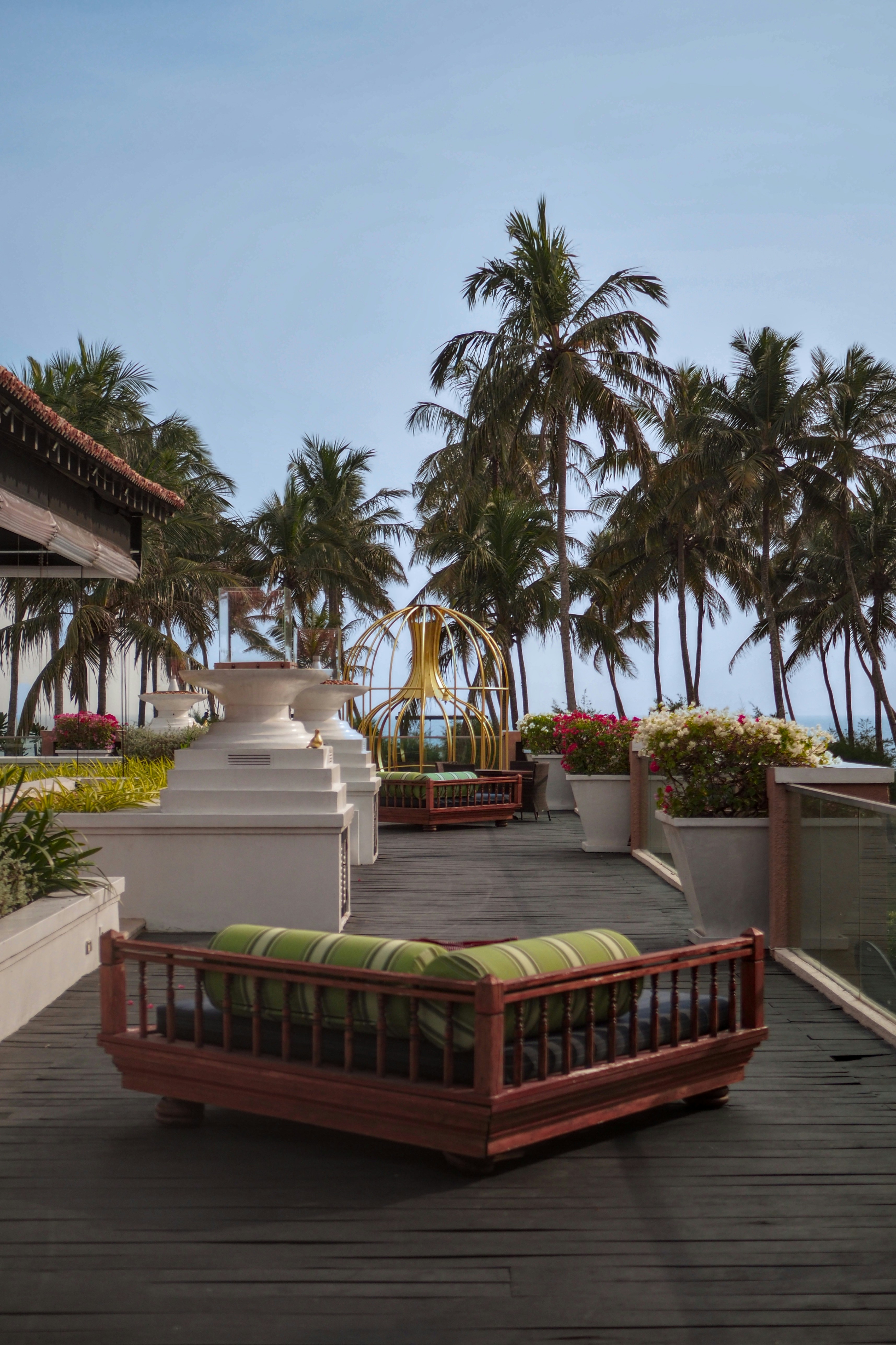 Sunlit Oceanfront Lounge: Palm Trees, Carved Seating, and Golden Orbs