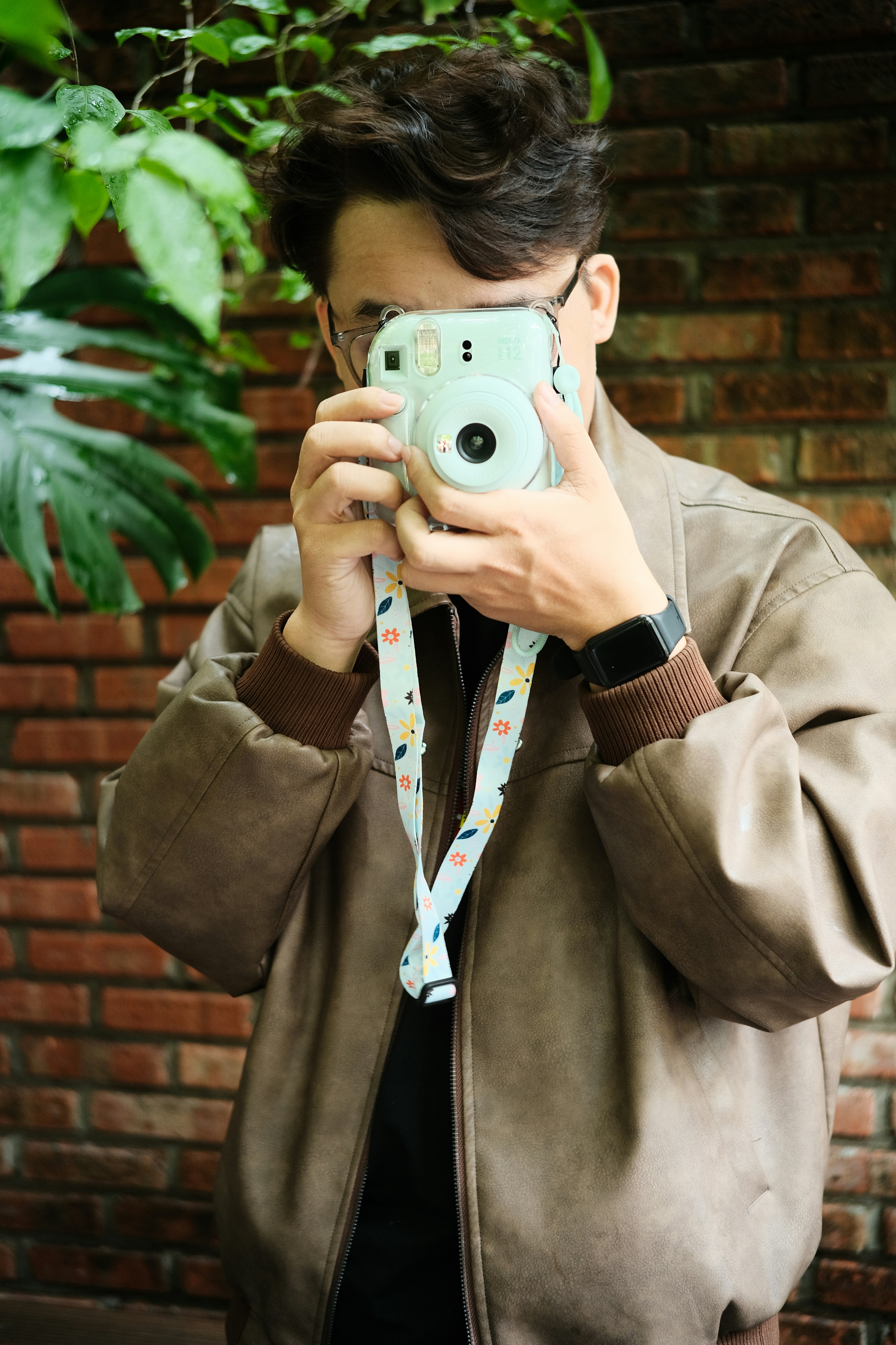 Soft-focus Portrait of a Photographer with Mint Camera Against Brick Backdrop