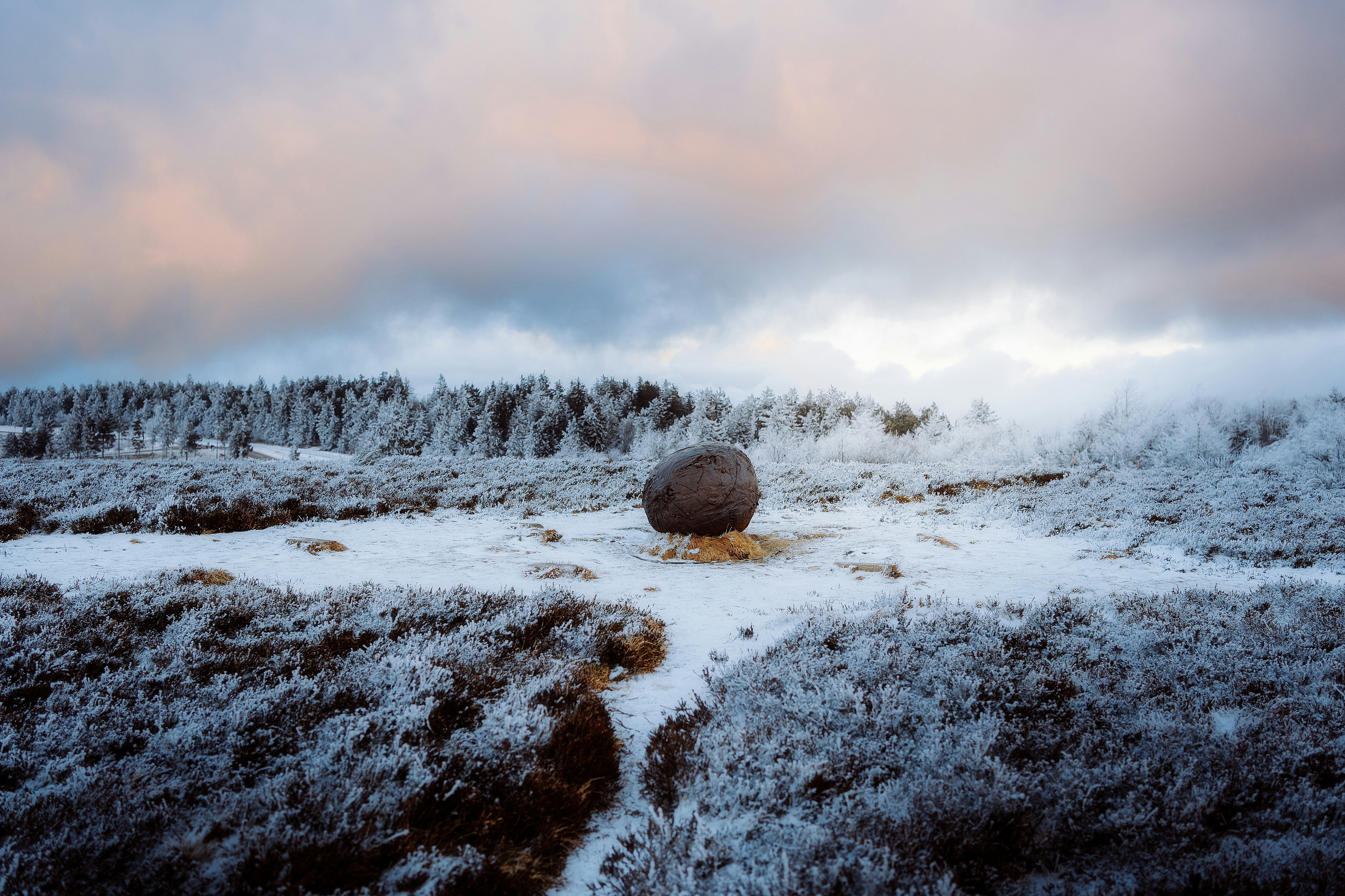 A solitary stone on a frost-kissed plain under pastel dusk