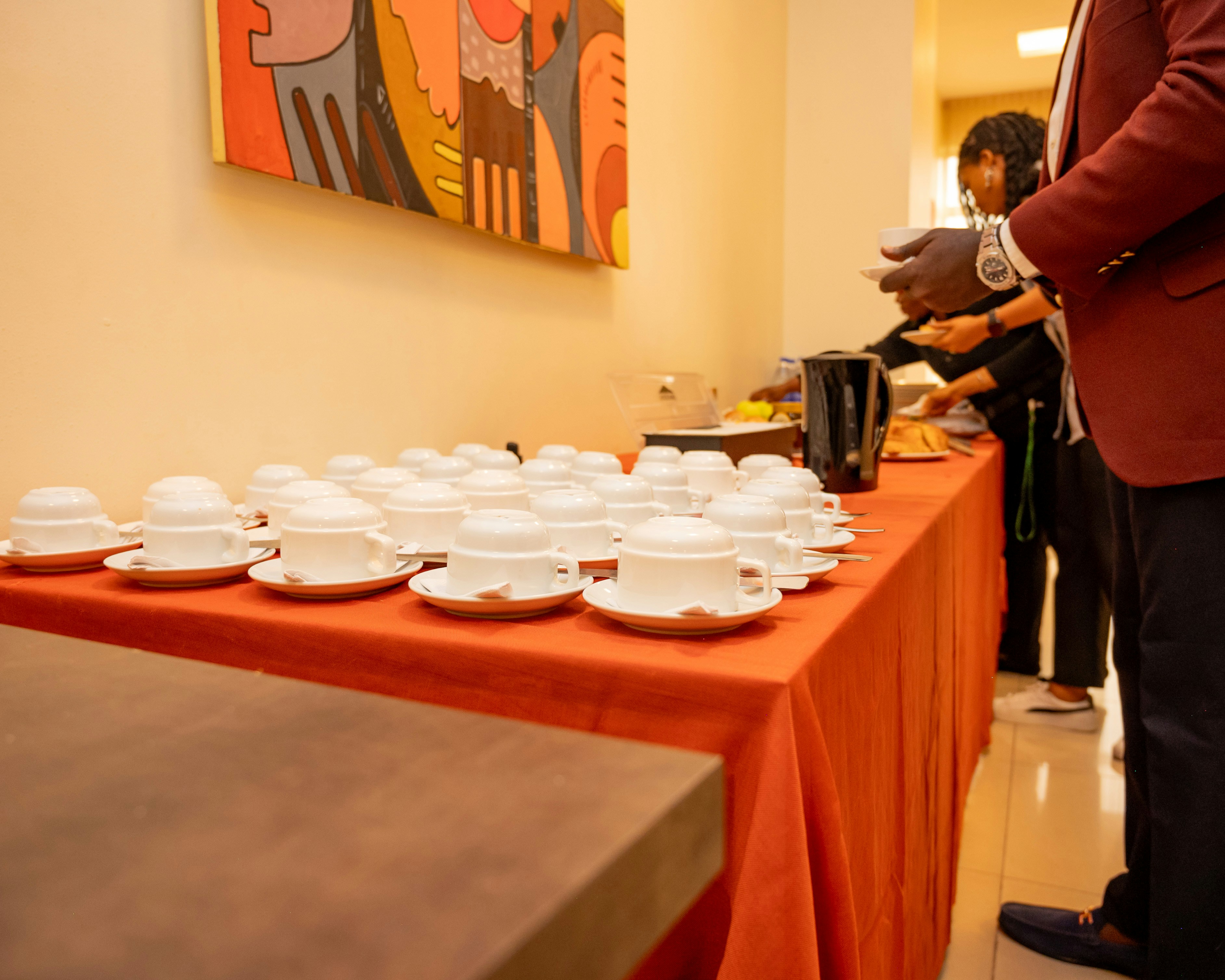 Tray of white cups on a red tablecloth at a catered refreshment station