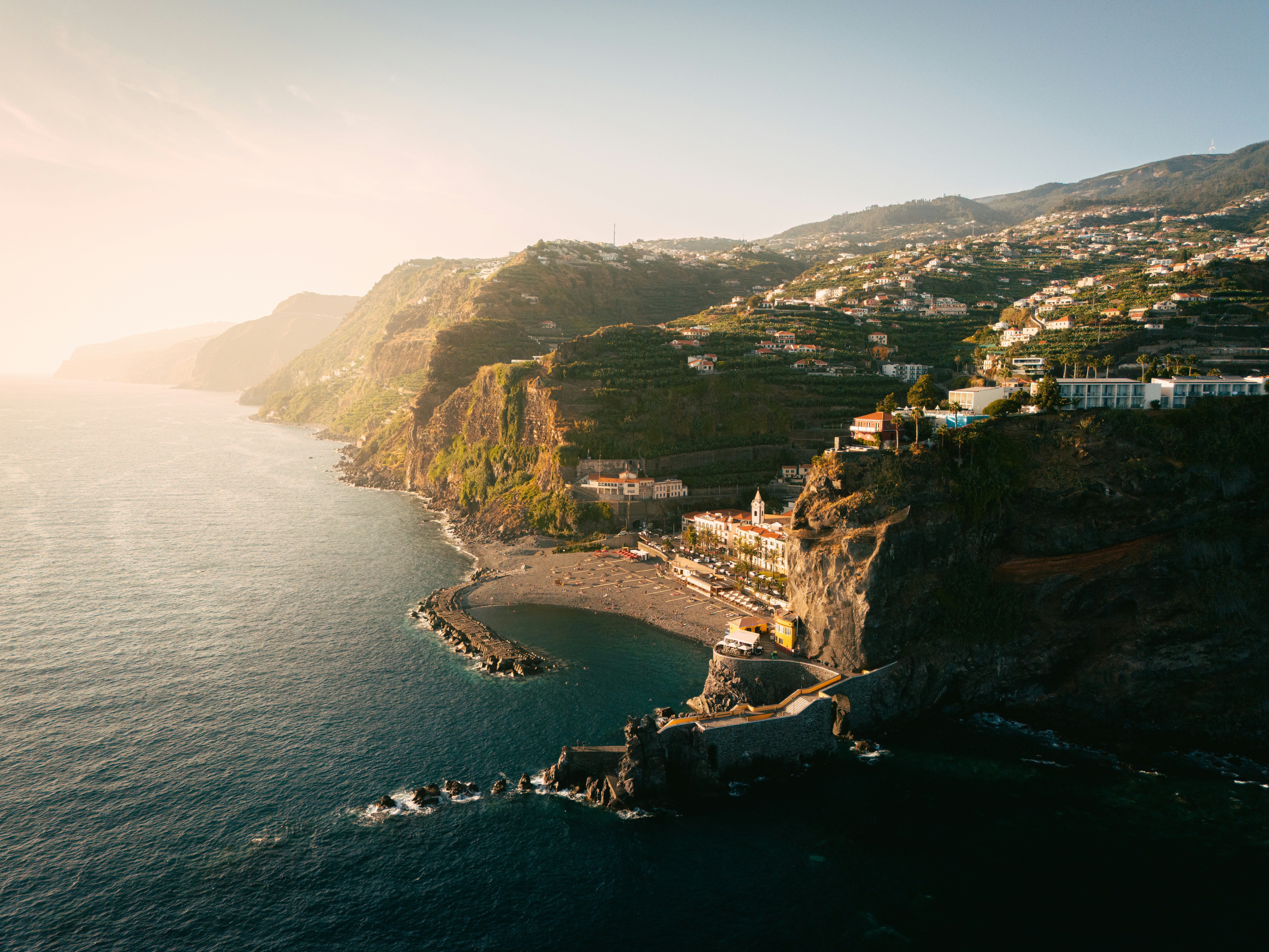Sunlit cliffside village glows along a tranquil Atlantic shore