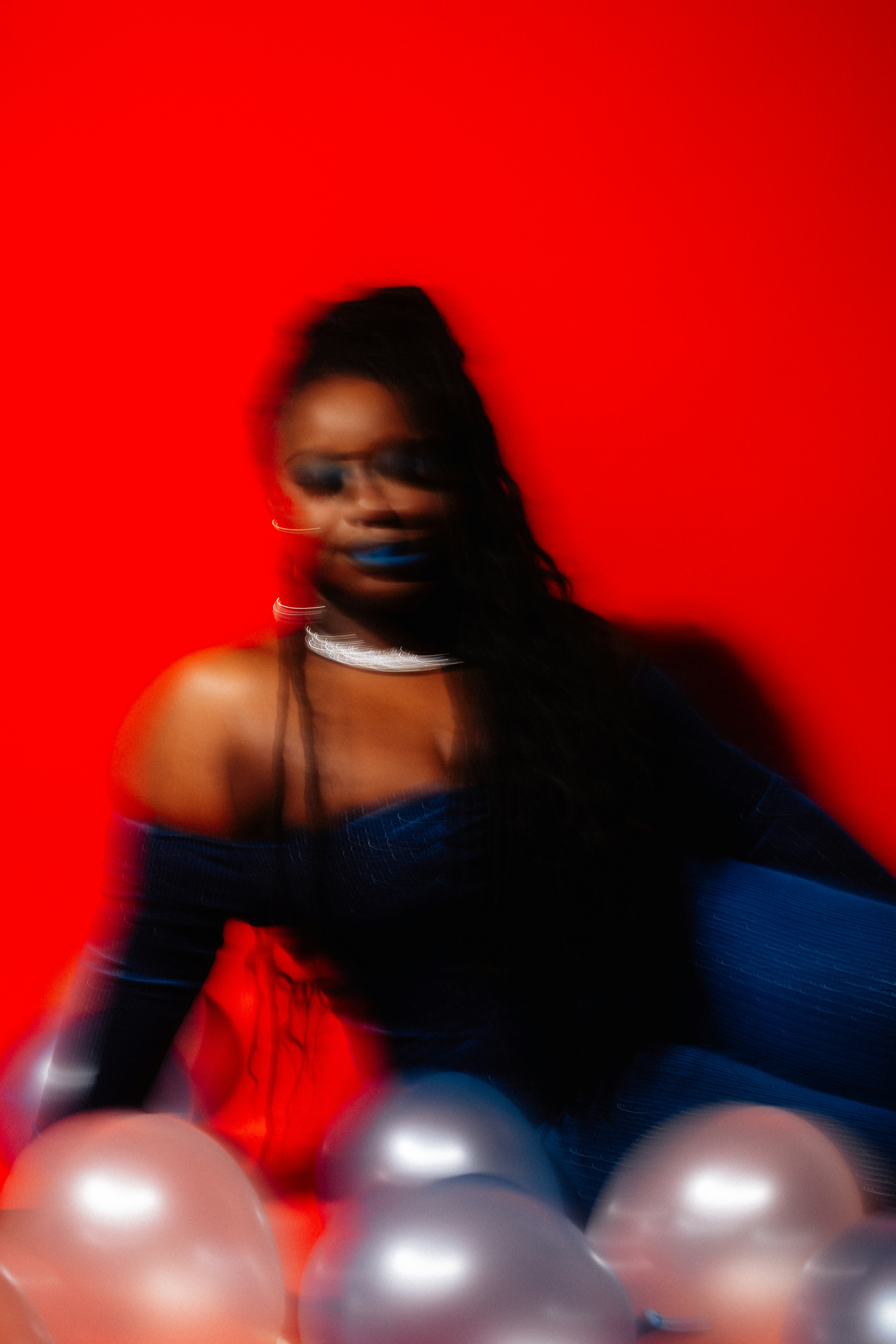Neon Red Backdrop Serenade: A Blurred Portrait with Balloons