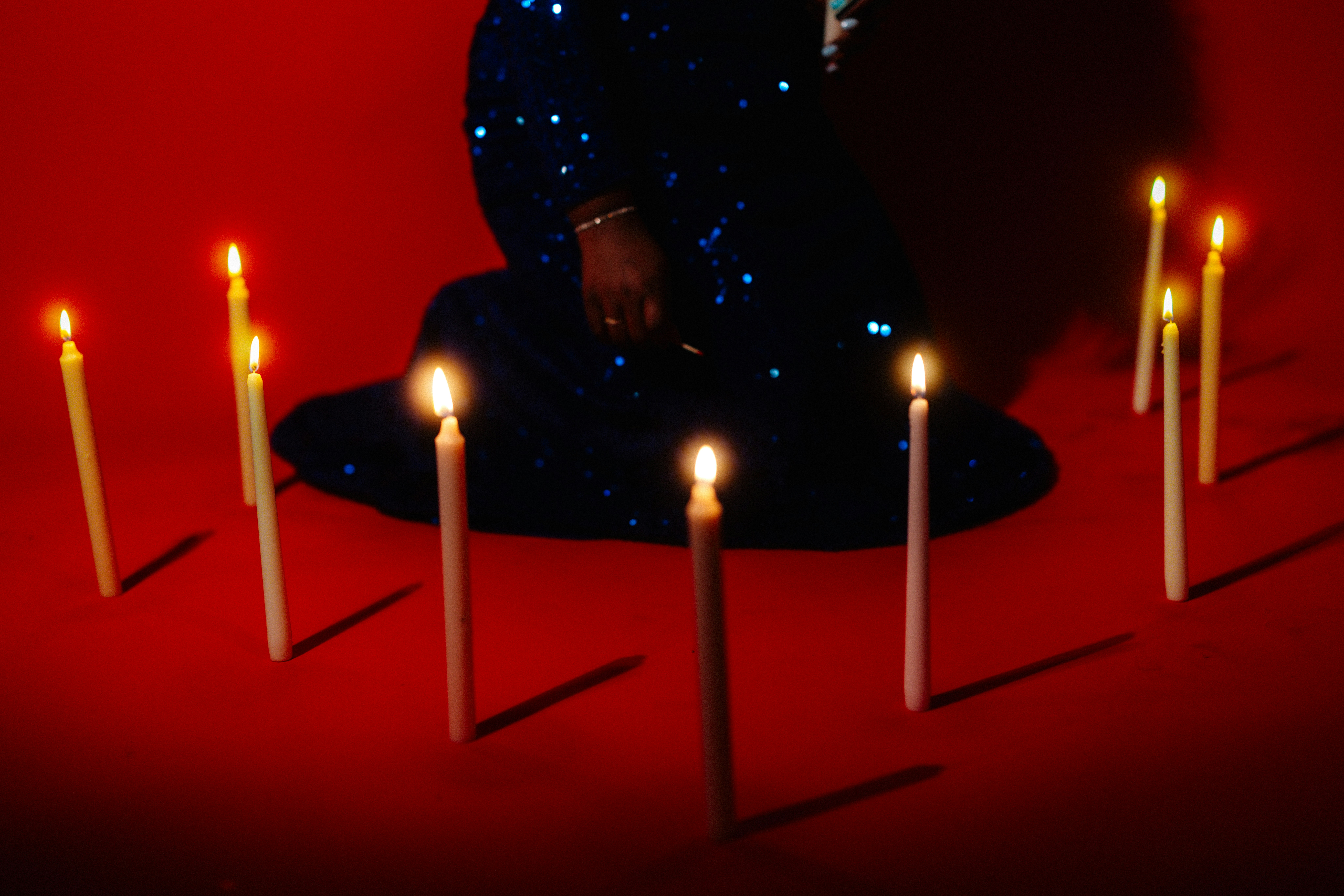 Candles Orbit a Hidden Silhouette in a Crimson Stage