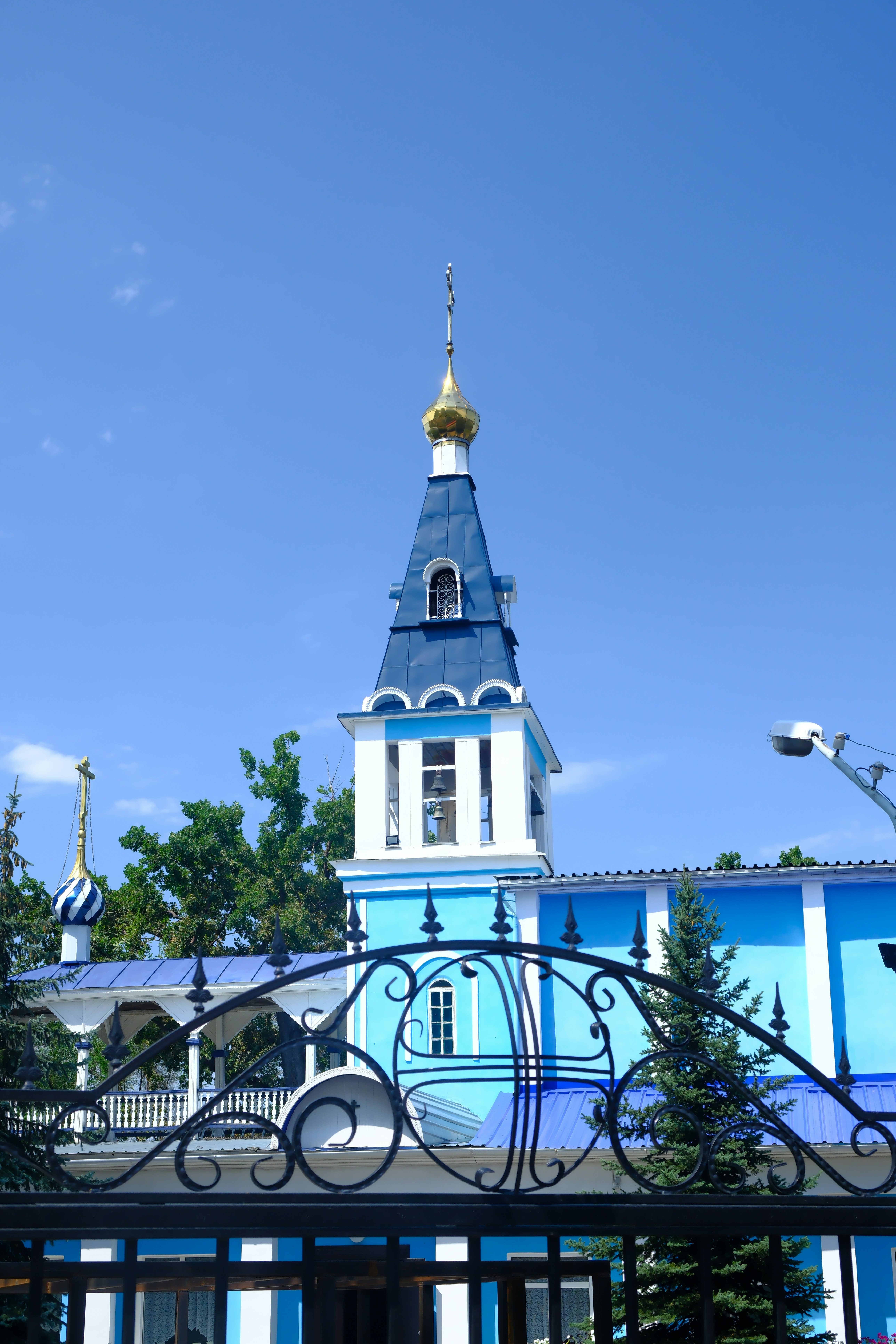 Blue-touched Chapel Spire Rising Over Ornate Black Gate