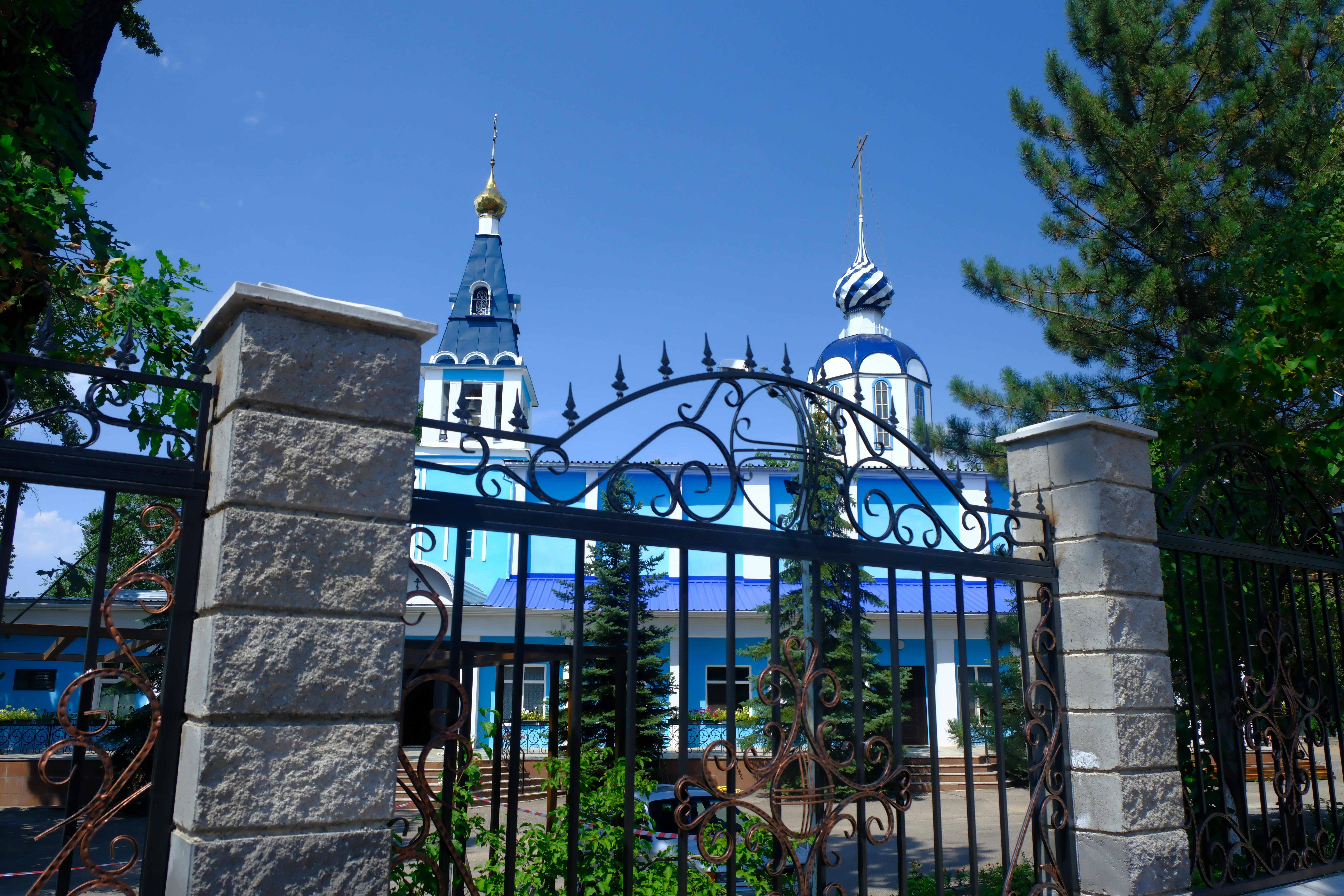 Blue-roofed sanctuary behind ornate wrought-iron gates