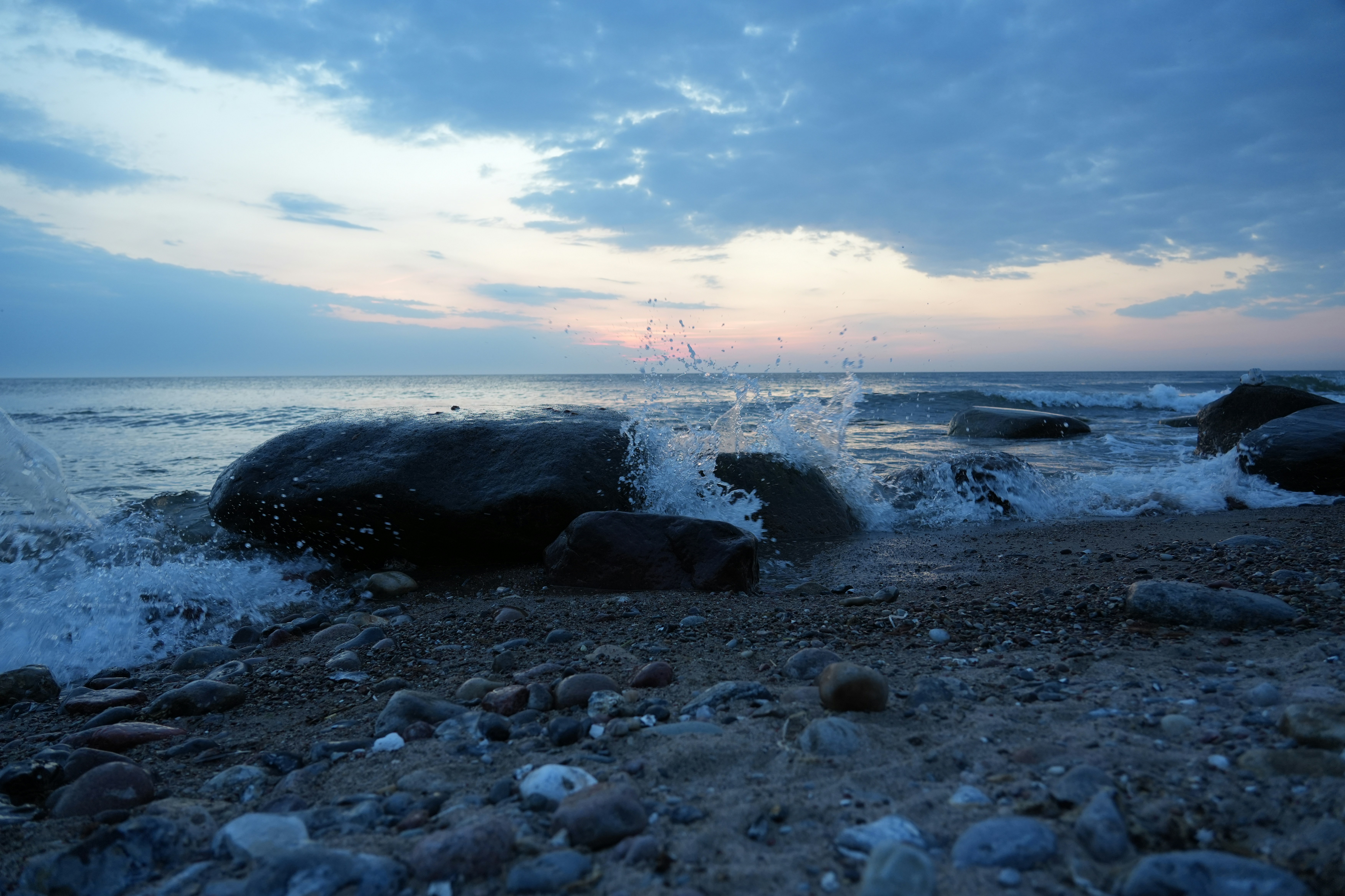 Sea spray at dusk: rocks and pebbles meeting the horizon