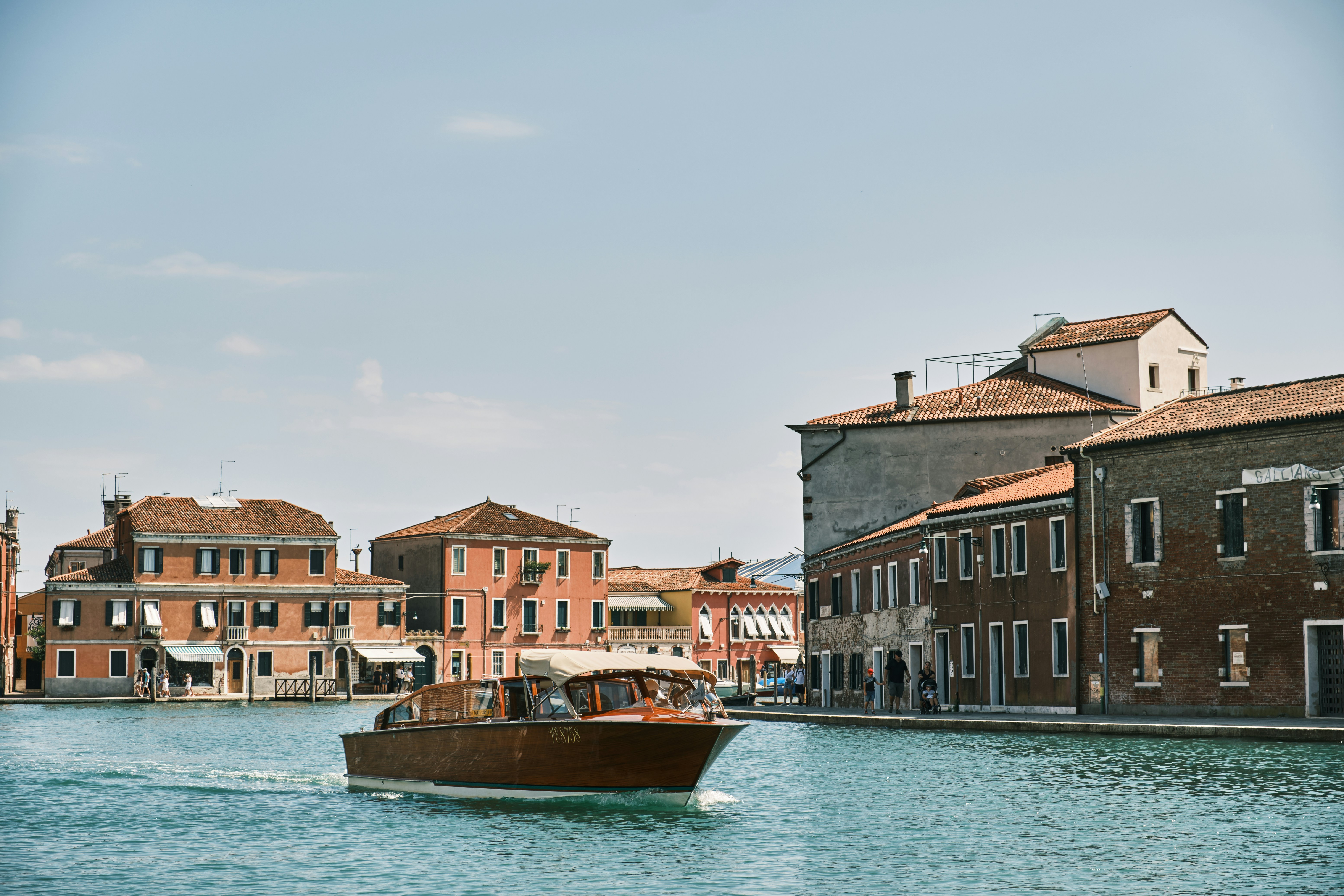 Vessel gliding past sunlit Venetian-style canal facades
