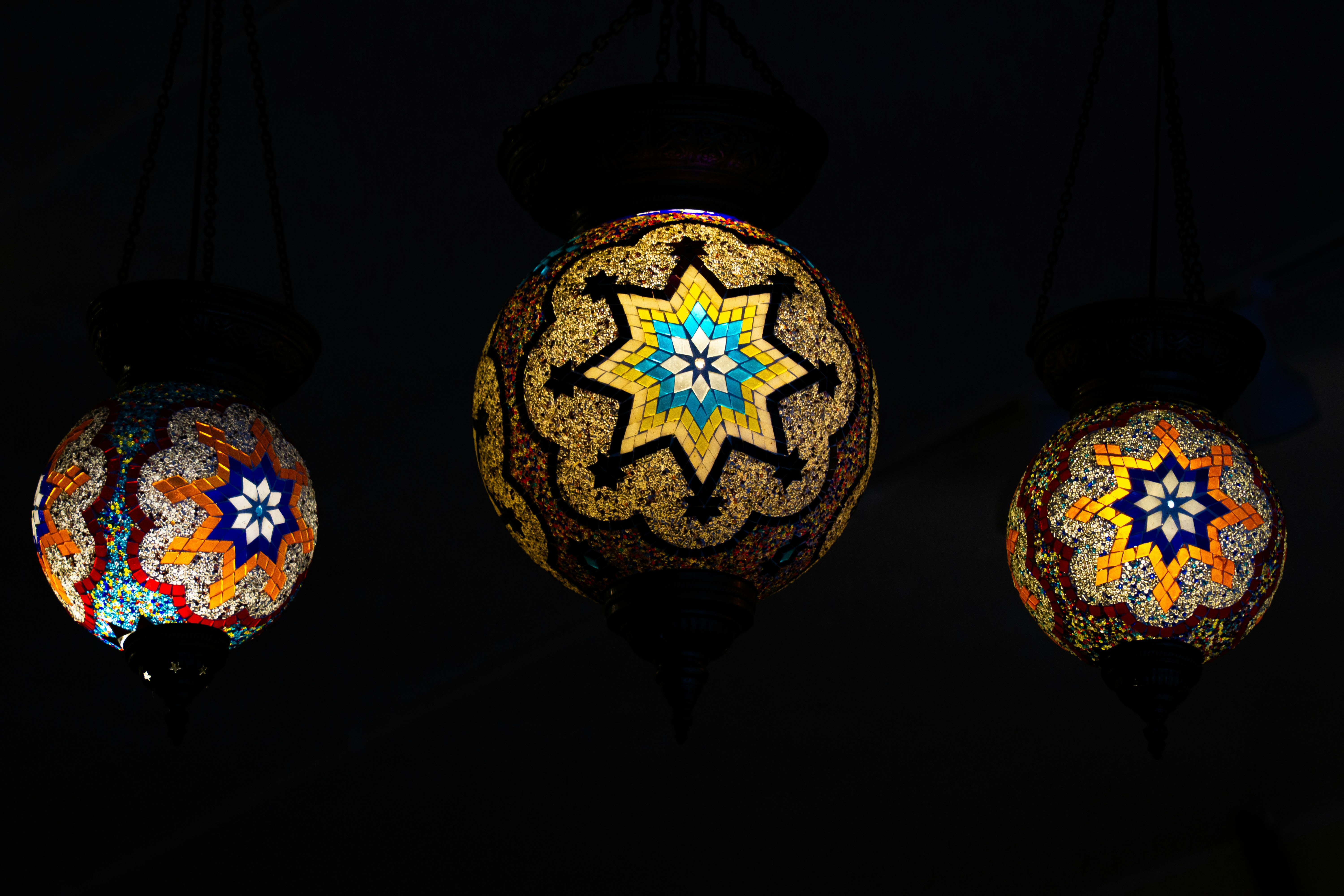 Triple Lantern Mosaic: Central Star glow in a darkened gallery