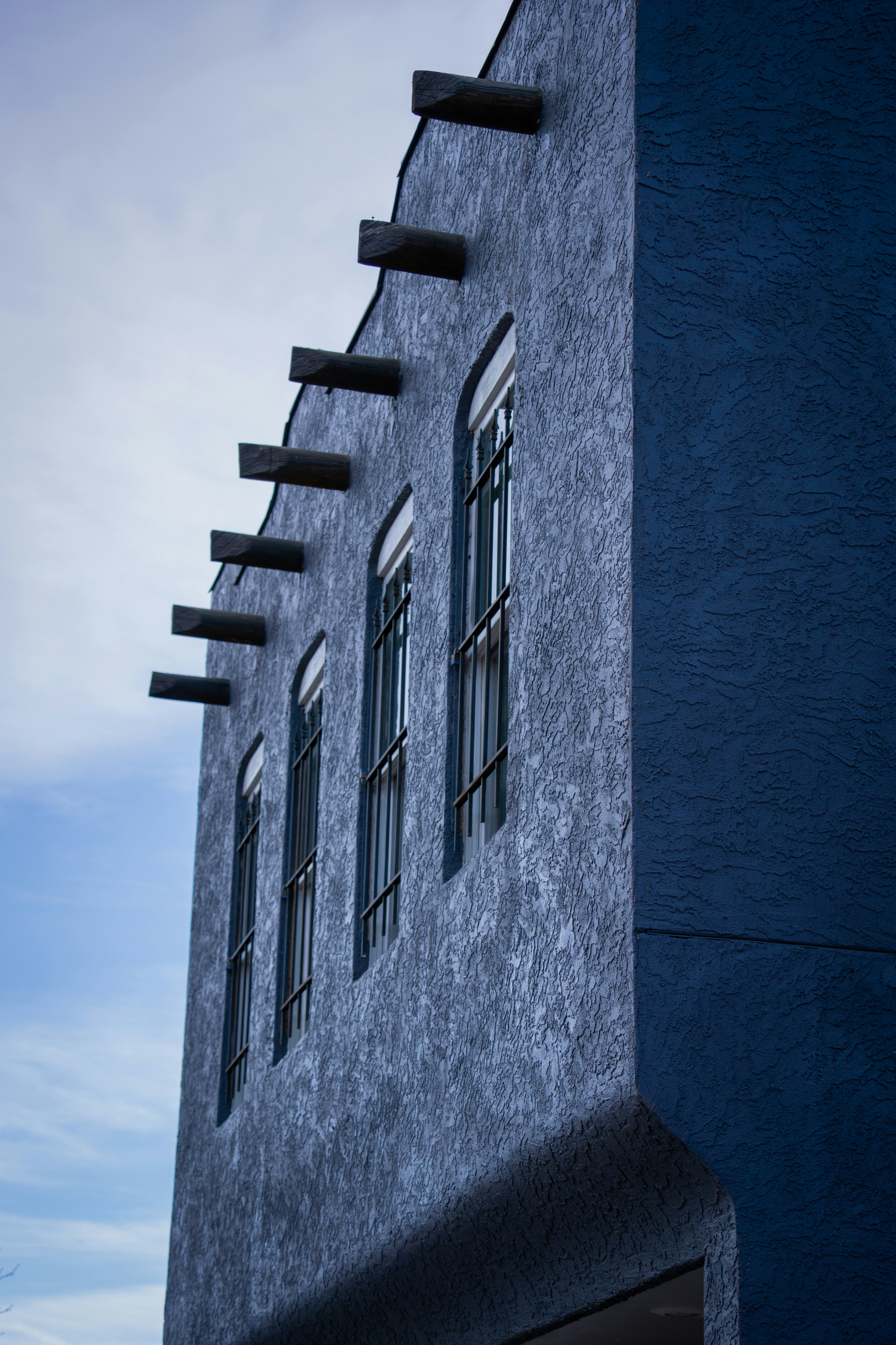 Azure Facade: A Leaning Wall of Windows and Wood Accents