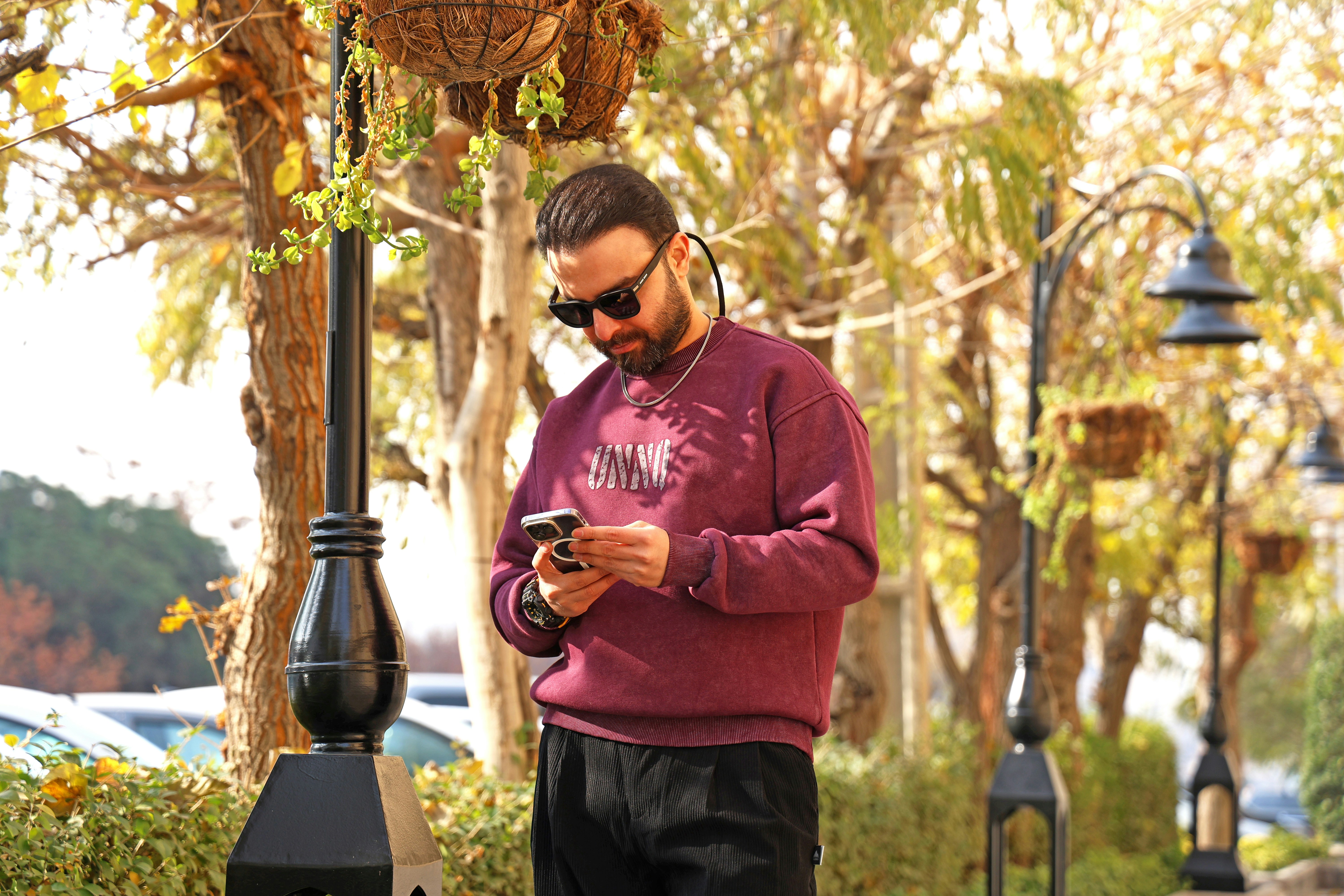 Boulevard of Screens: Man in Cherry Sweatshirt Immersed in Mobile Moment