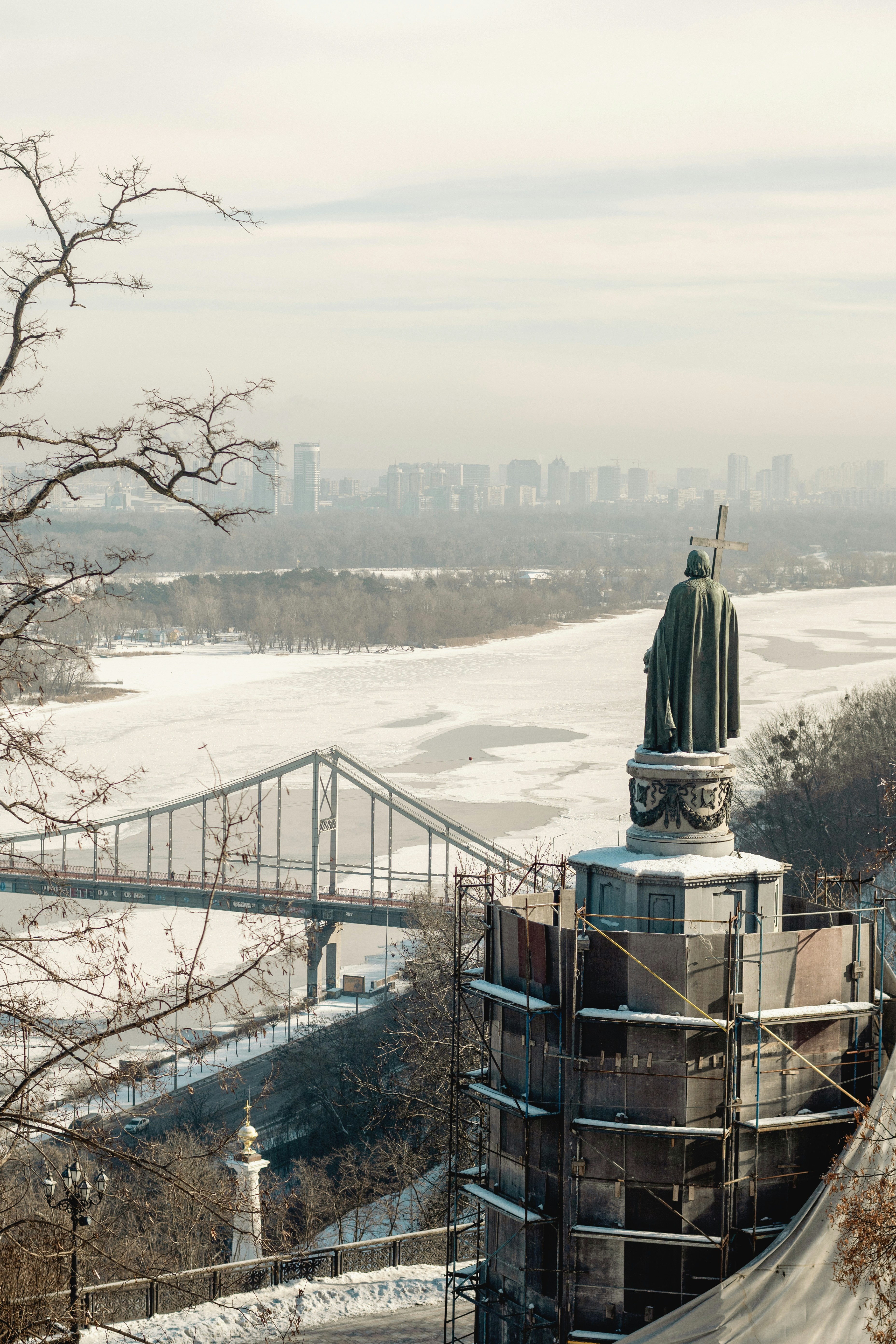 Statue Overlooking a Winter City: Bridge, River, and Skyline