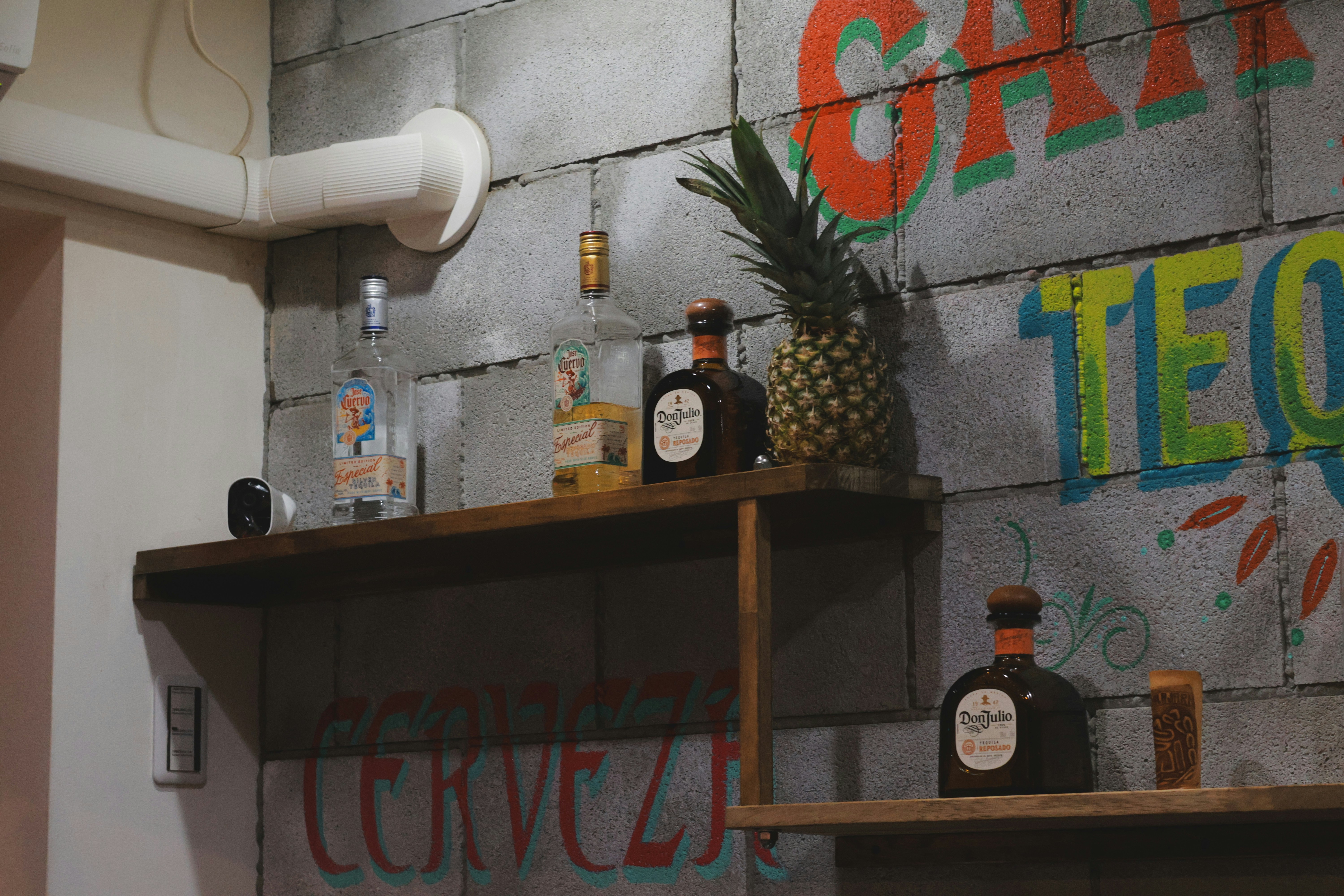 Shelf of Bottles Under Graffiti Wall