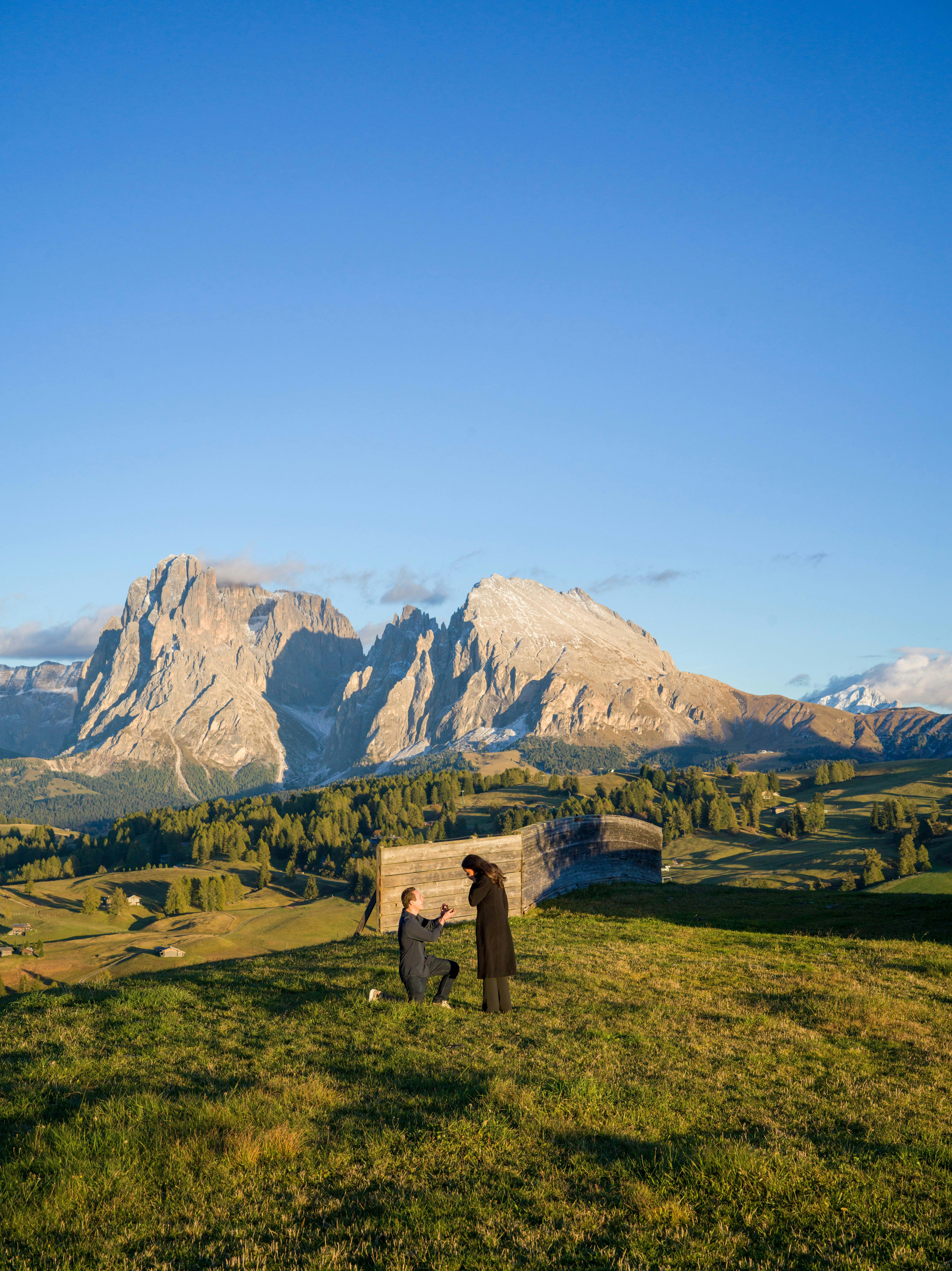A Quiet Moment in the Alpine Field: A Couple on a Hill with the Majestic Ridge Behind