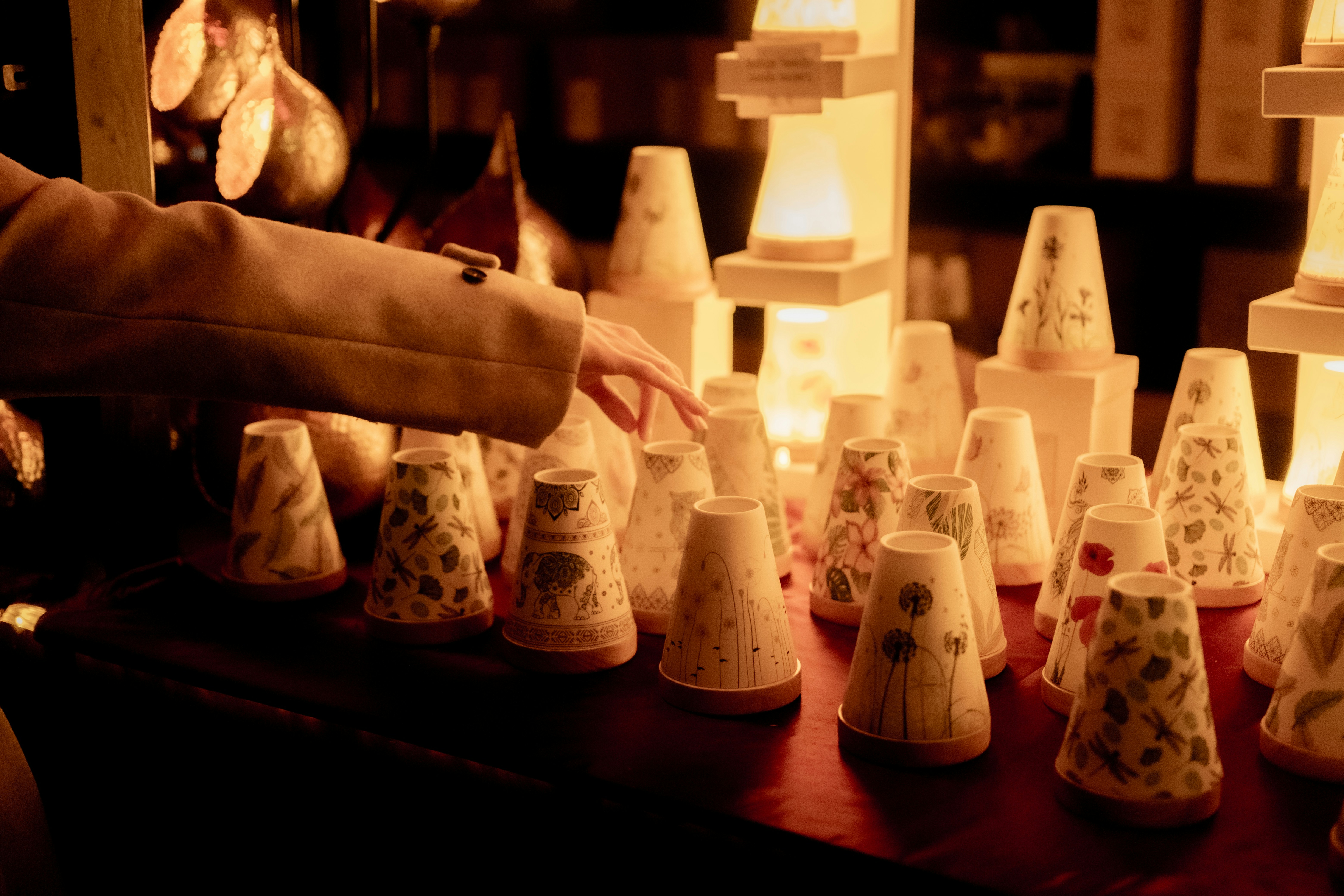Cup Mosaic: Hand Reaches Among Painted Ceramics in Warm Display