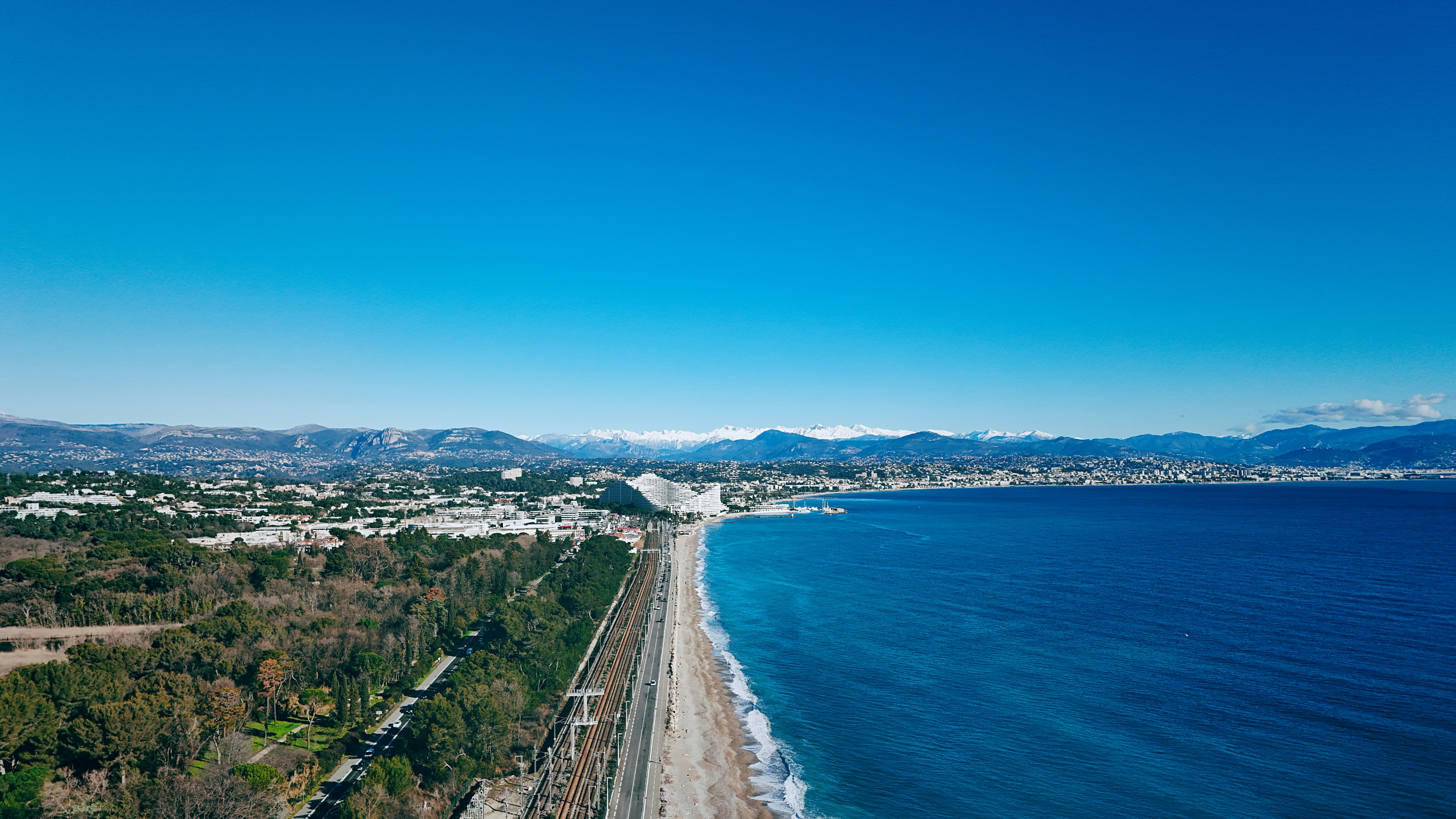 Coastal city with train tracks along the blue ocean.