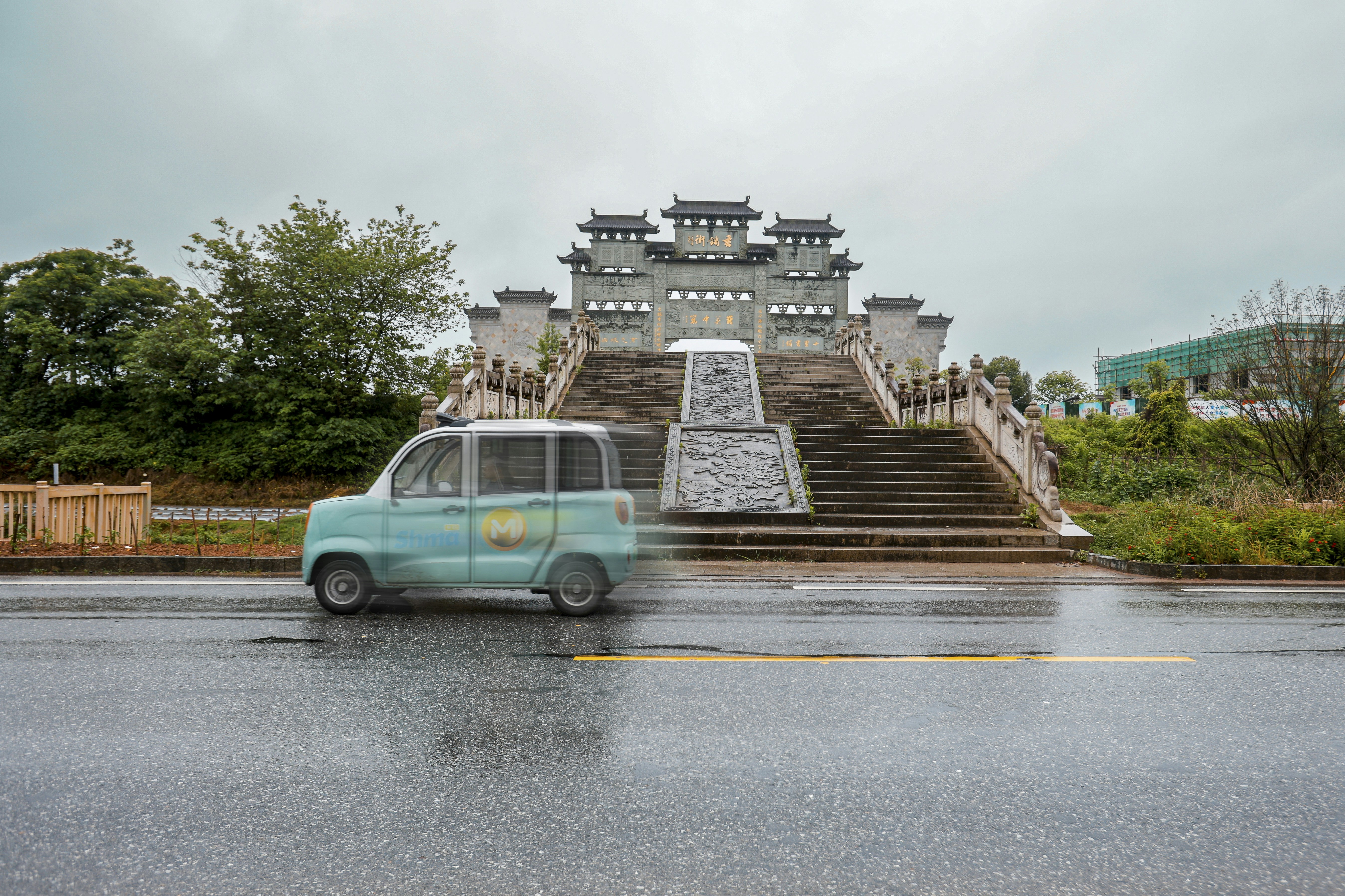Blue van crosses the wide stone staircase toward an ornate pavilion