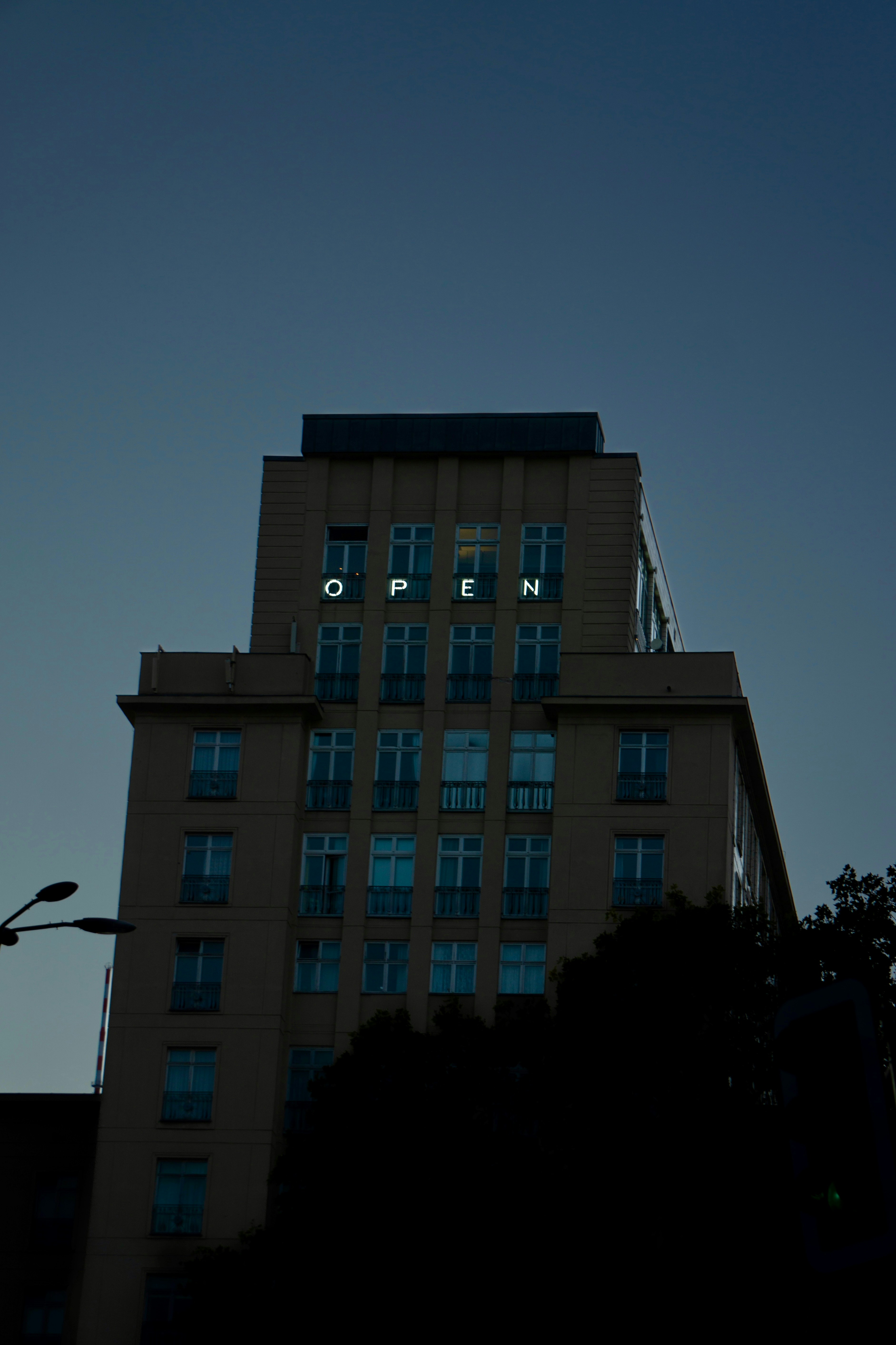 Evening Facade: The Open Window Signage Lights Up a Quiet Sky