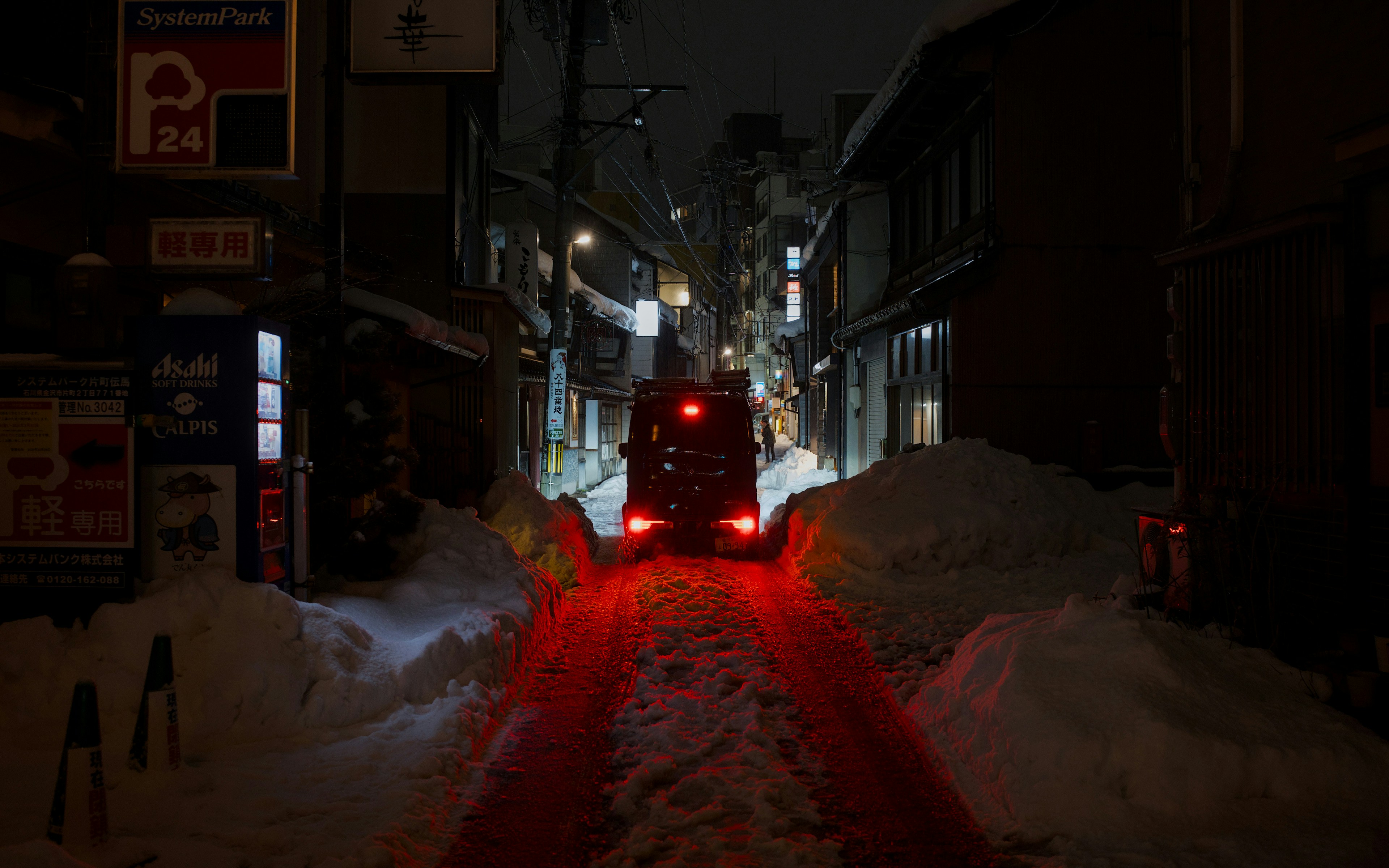 Red taillight corridor: a snowy alleyway vanishes into night