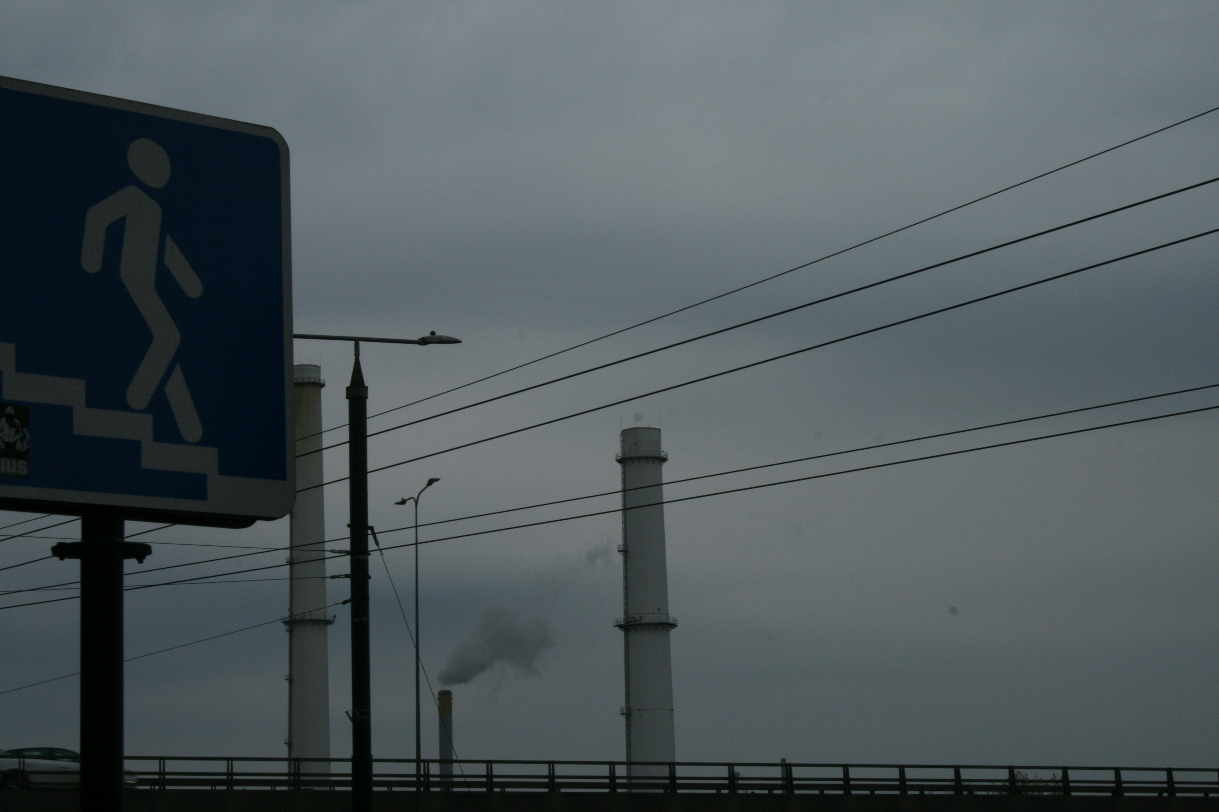 Industrial skyline under subdued gray skies with a pedestrian sign silhouette