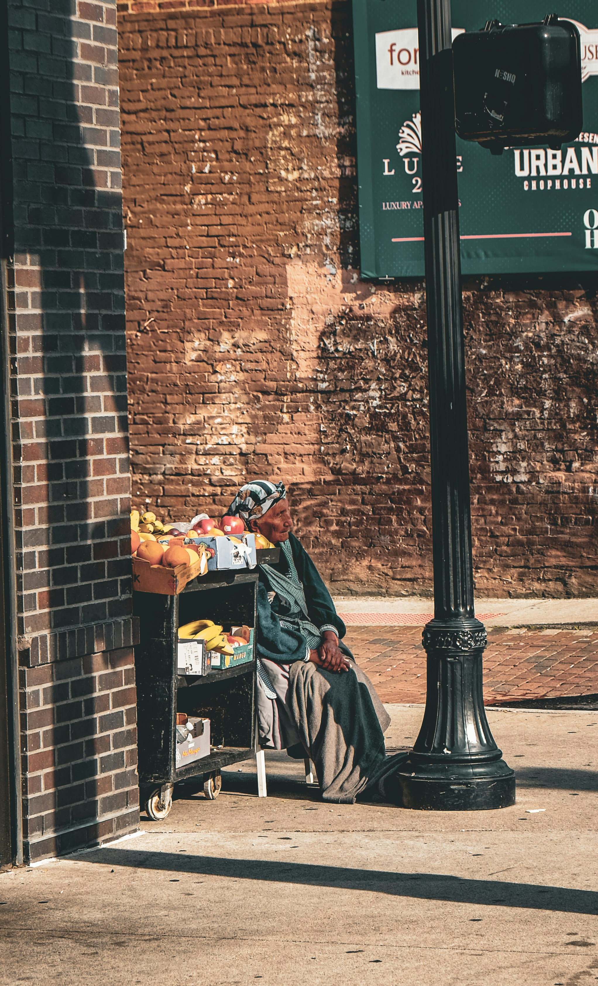 Street Vendor in Sunlit Alley by a Lamp Post