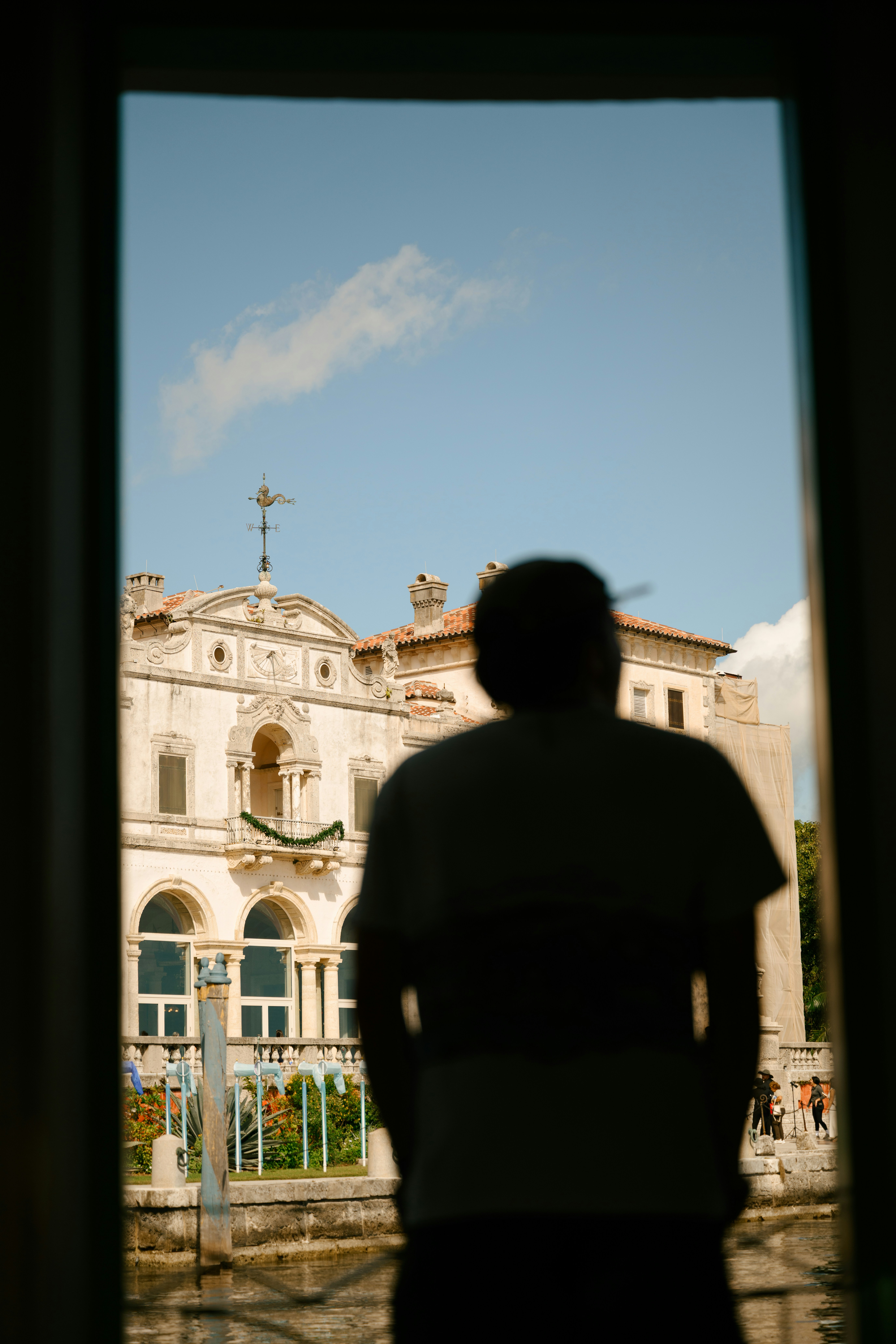Silhouette Over Courtyard: A Shadowed Visitor Framed by a Historic Facade