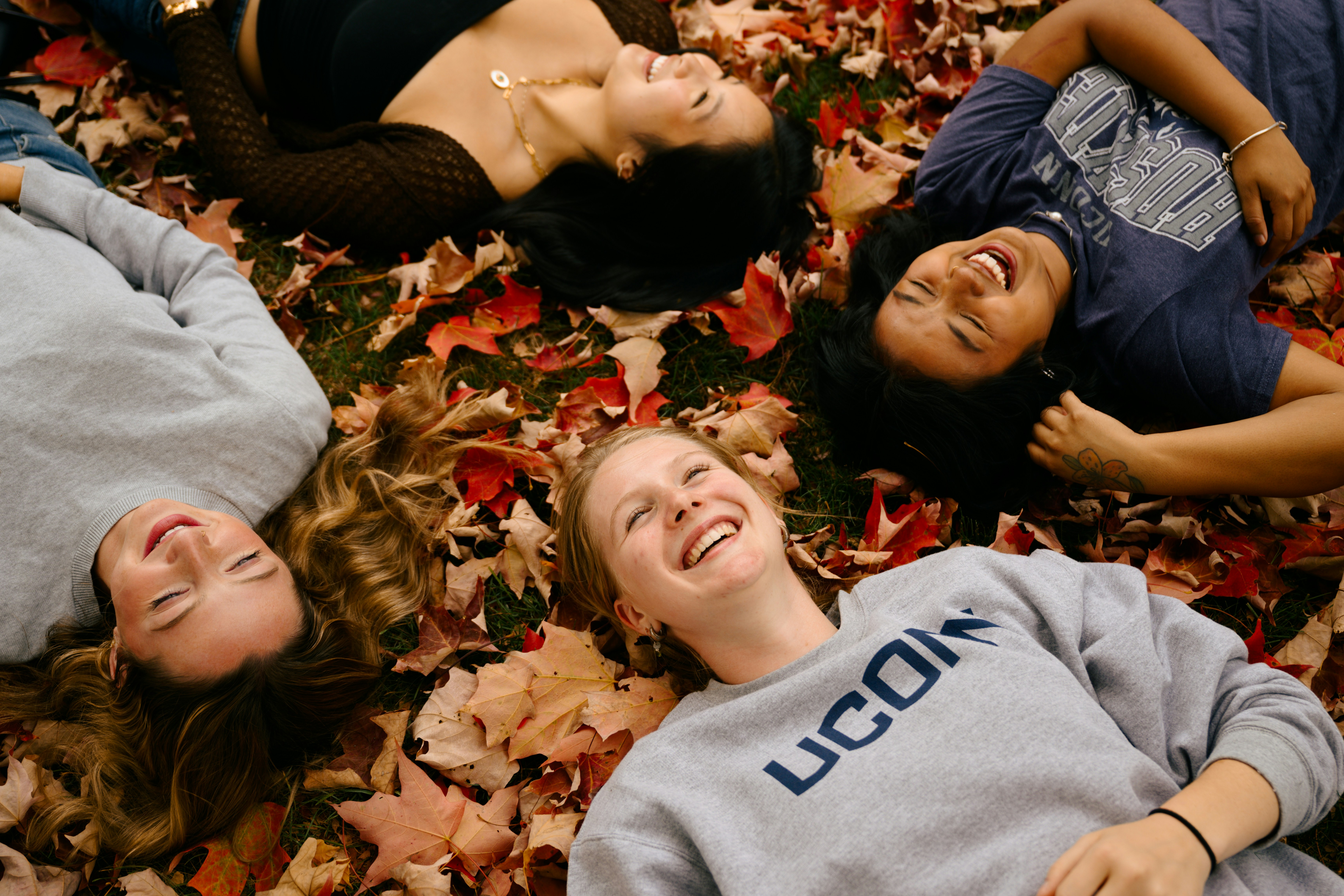 Circle of Colorful Leaves: Friends Lying Back-to-Back in Autumn Campus