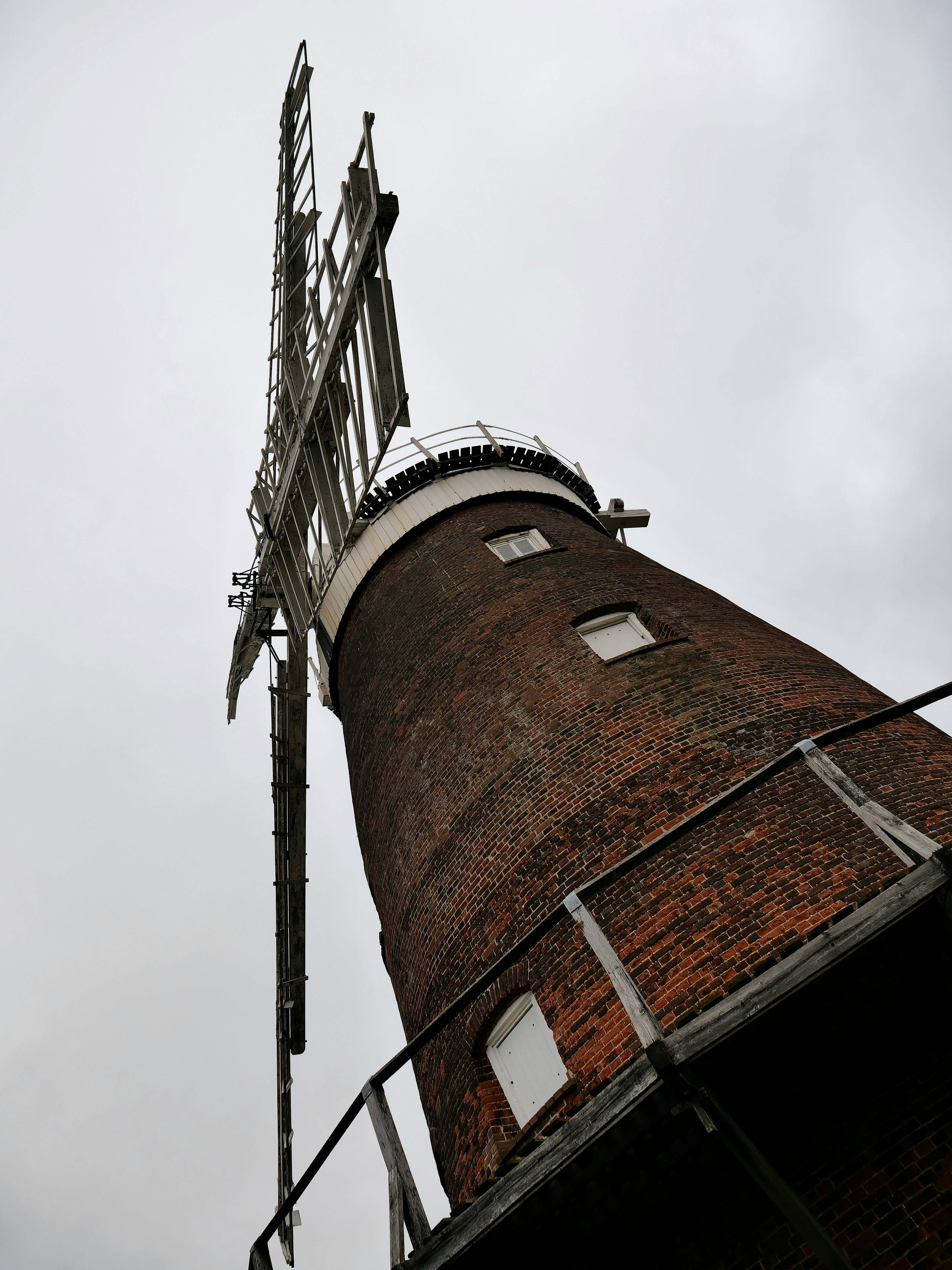 Brick Windmill with Weathered Blades Reaching Toward a Grey Sky