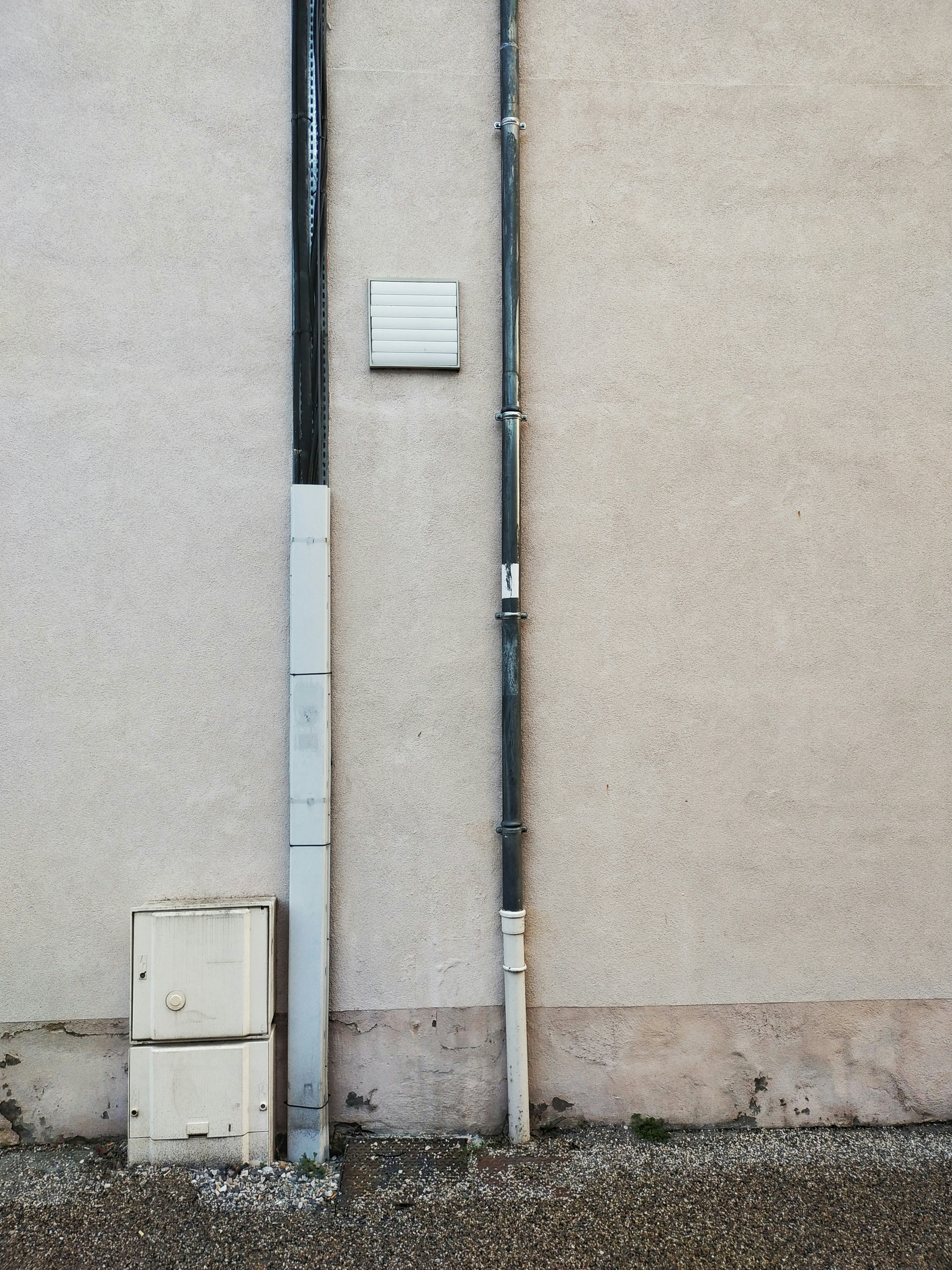 Two pipes and electrical boxes on a wall