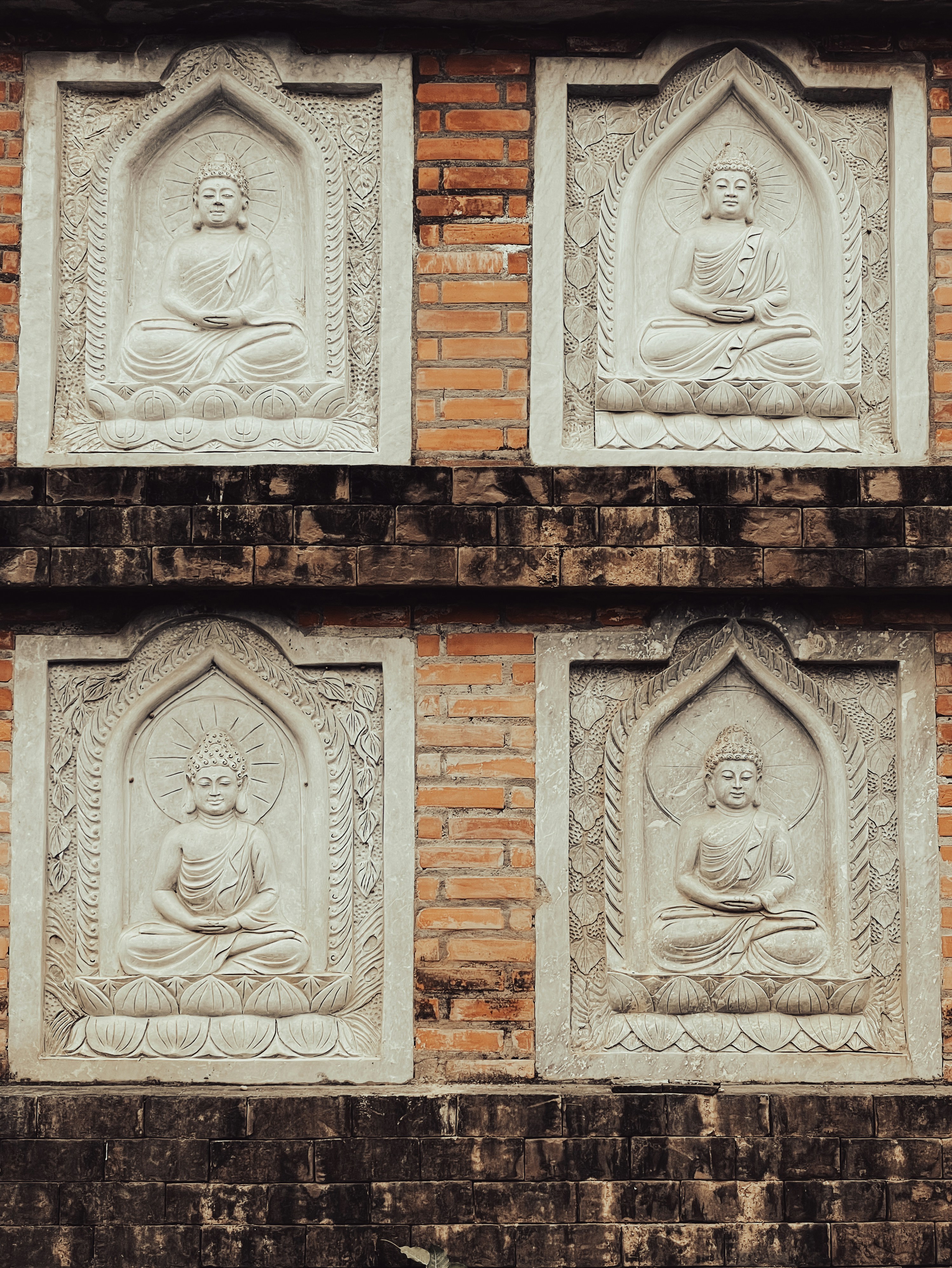 Quiet symmetry: four Buddha niches marching across a brick wall