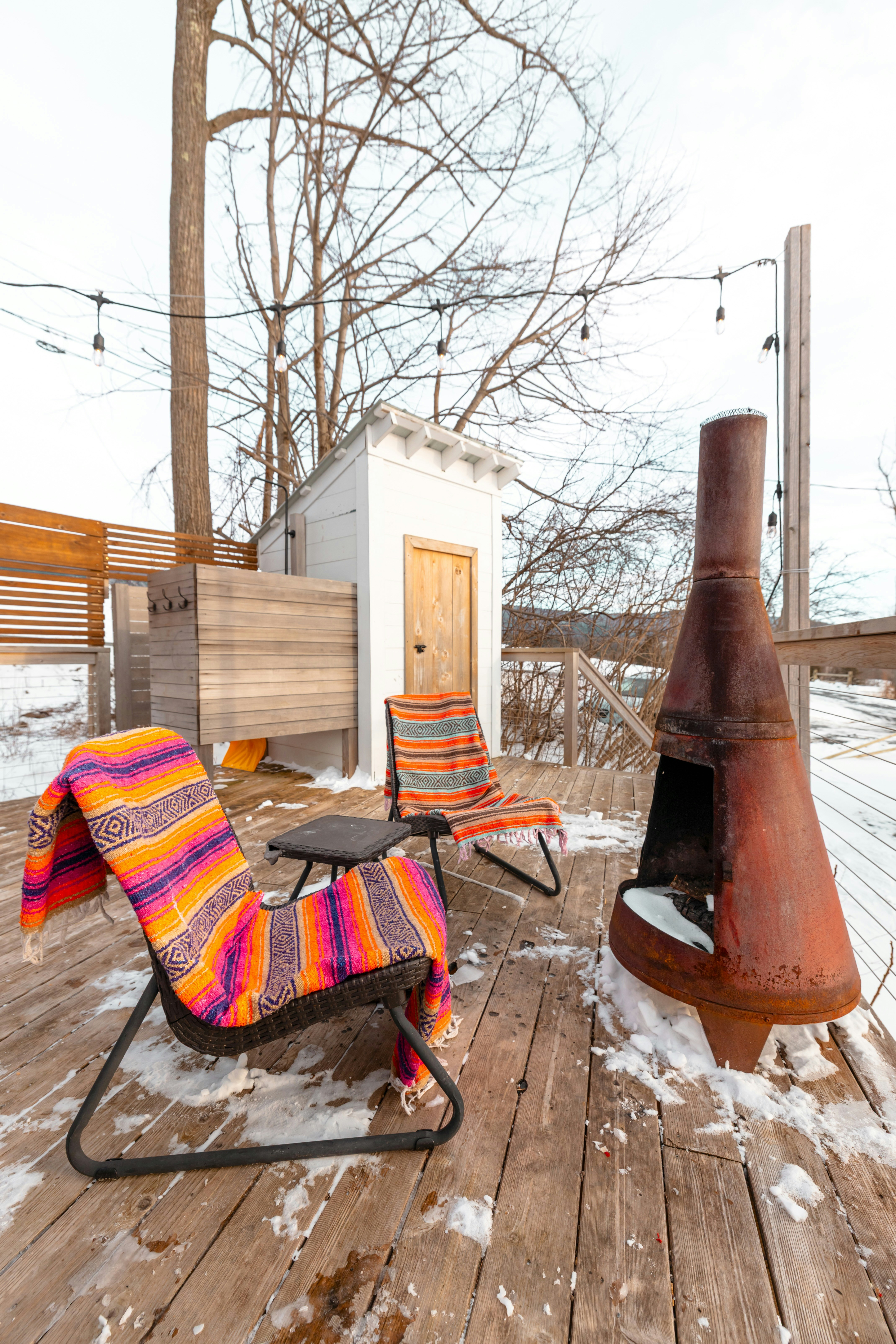 Cozy Winter Deck Scene: Painted Chairs, Fire Pit and Snow-dusted Wood