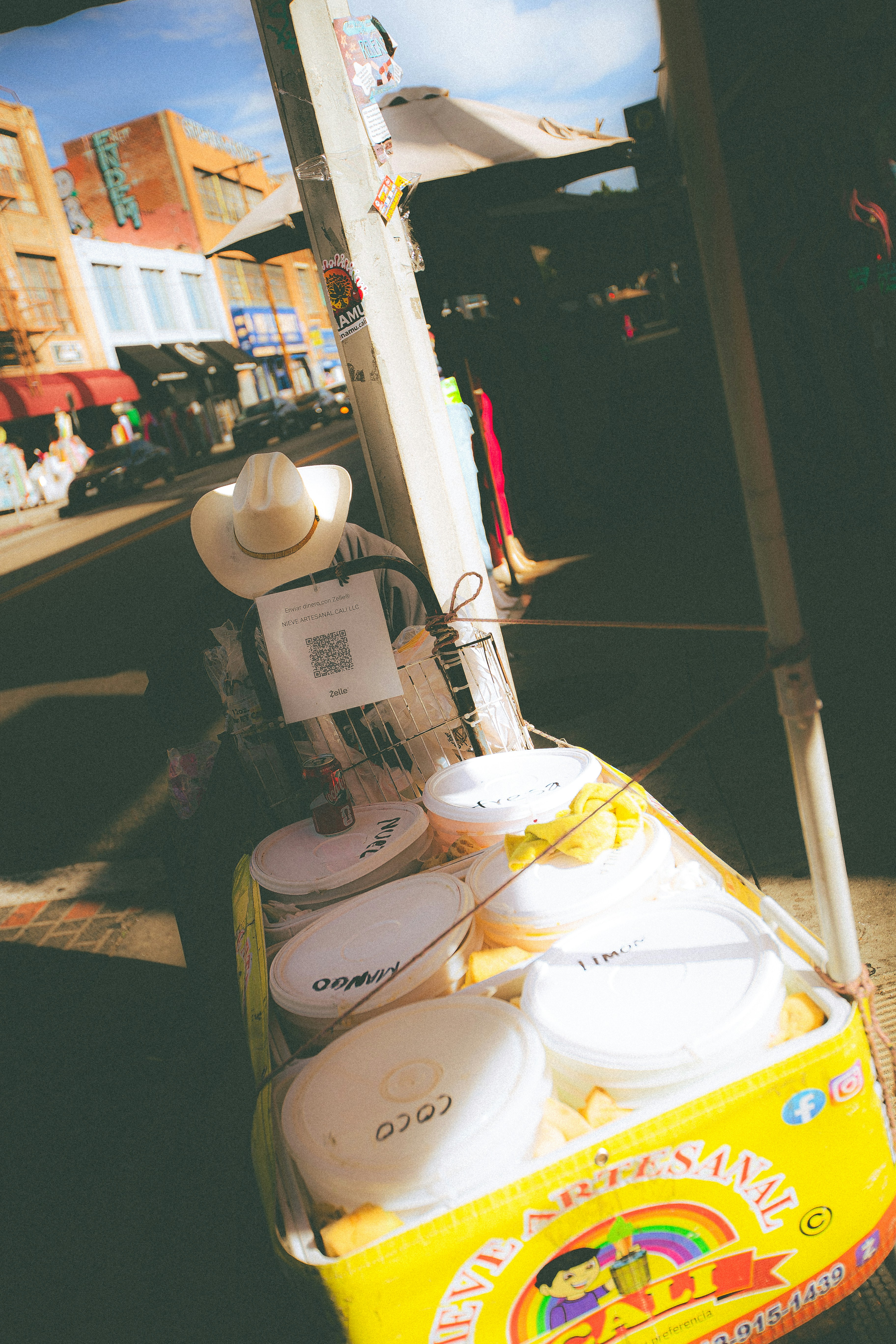 Sunlit Street Vendor with Yellow Ice Cream Cart and Wide-Brim Hat