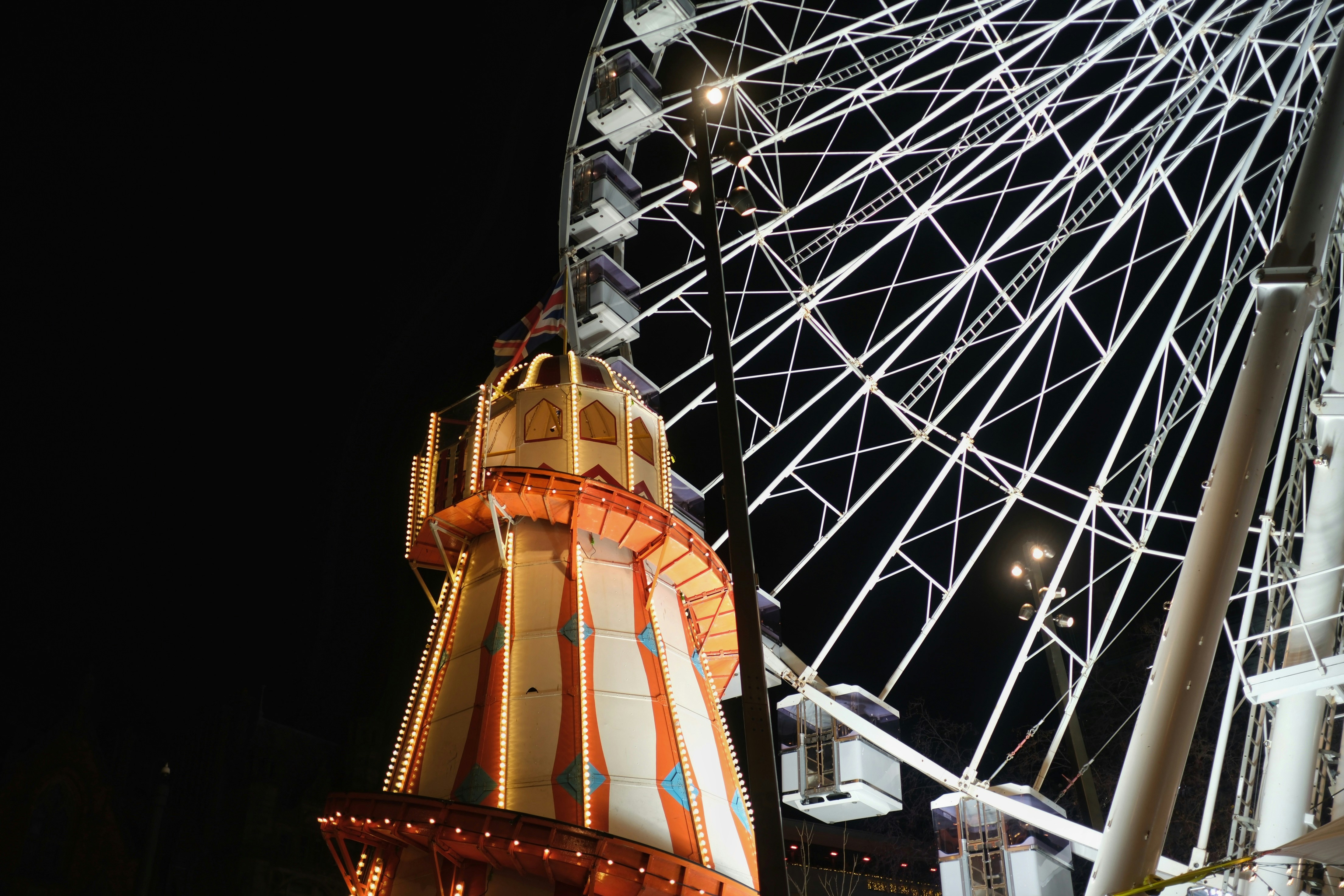 Ferris Wheel Lights Cast a Neon Halo Over a Tilted Carousel Spire