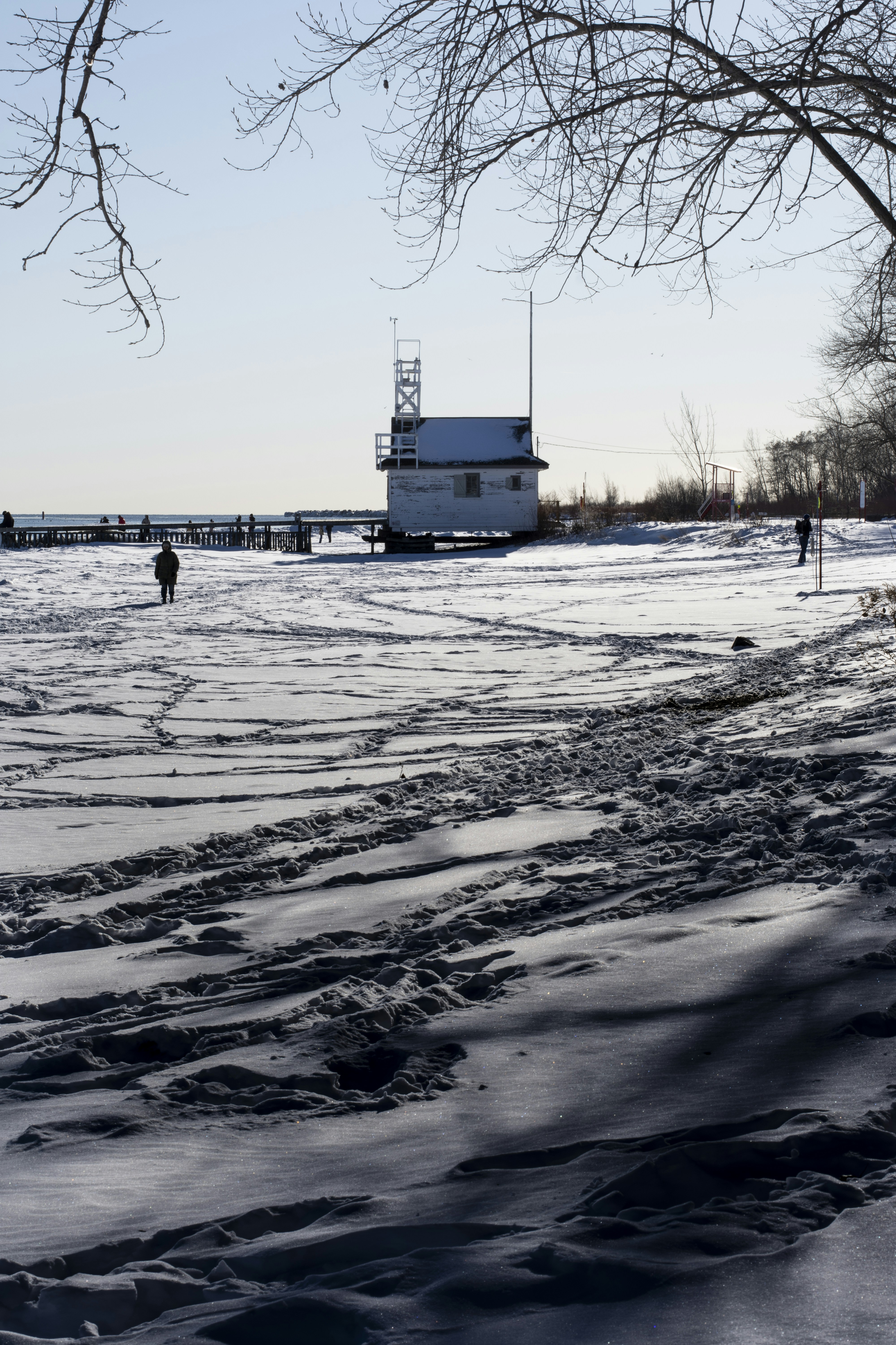 Winter Shoreline: A Snowbound Pier and Silhouetted Figures