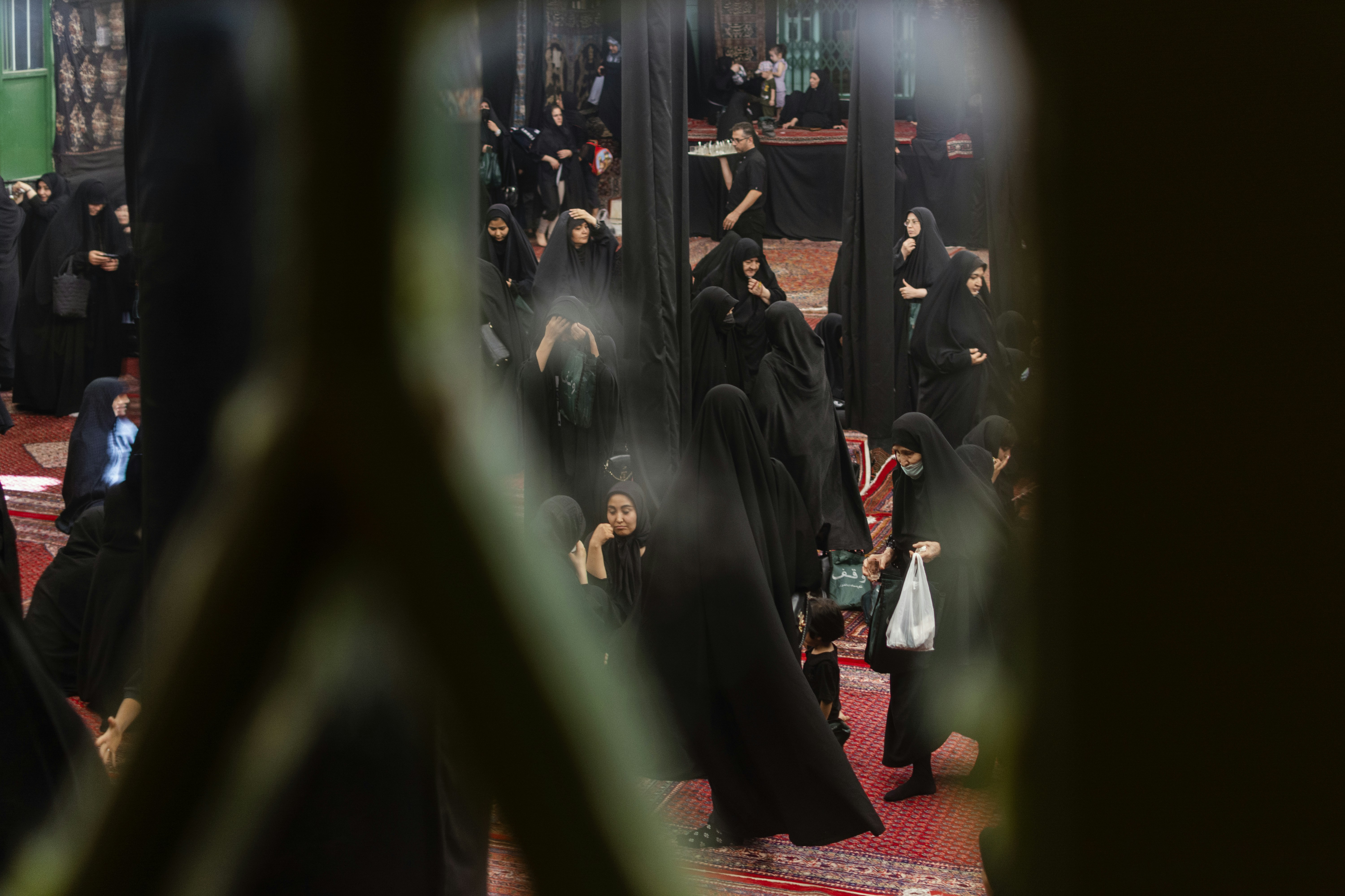 Hidden Rituals: Figures in a Red Carpet Shrine Framed by foreground silhouettes