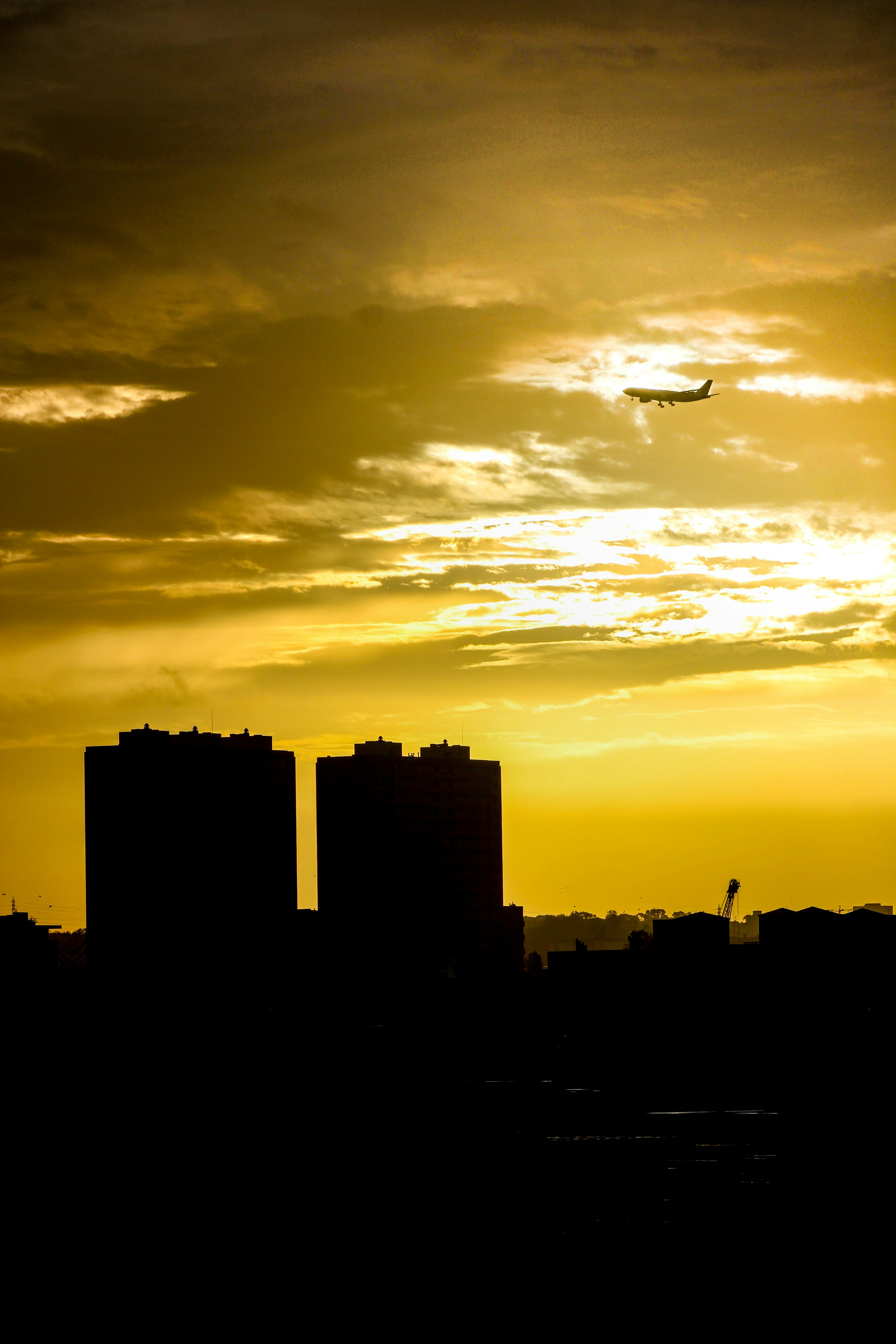 Golden Hour Descent: Airplane Silhouette Over an Urban Horizon
