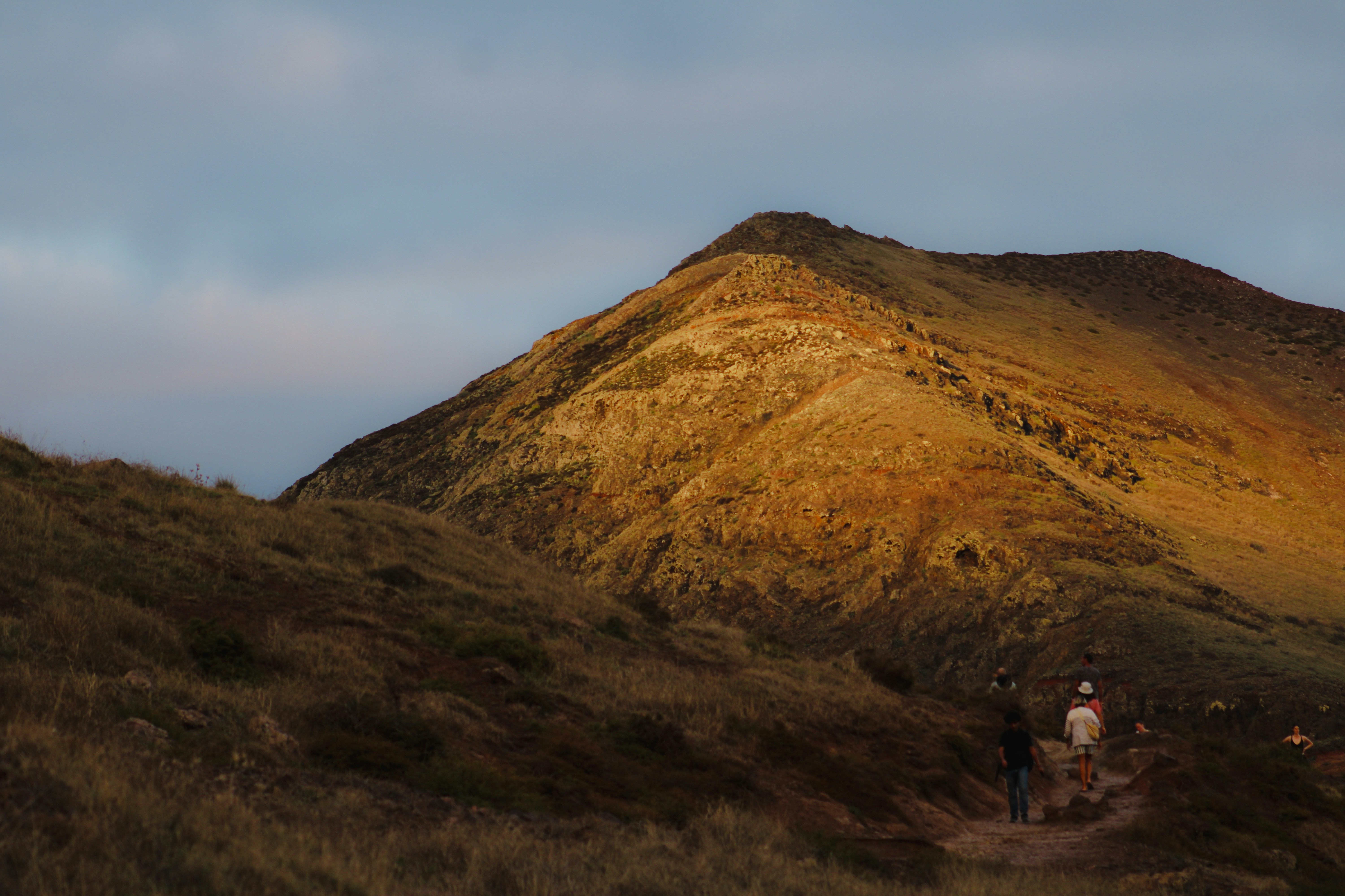 Golden Crest: Hikers in the Shadowed Valley of the Sunlit Peak