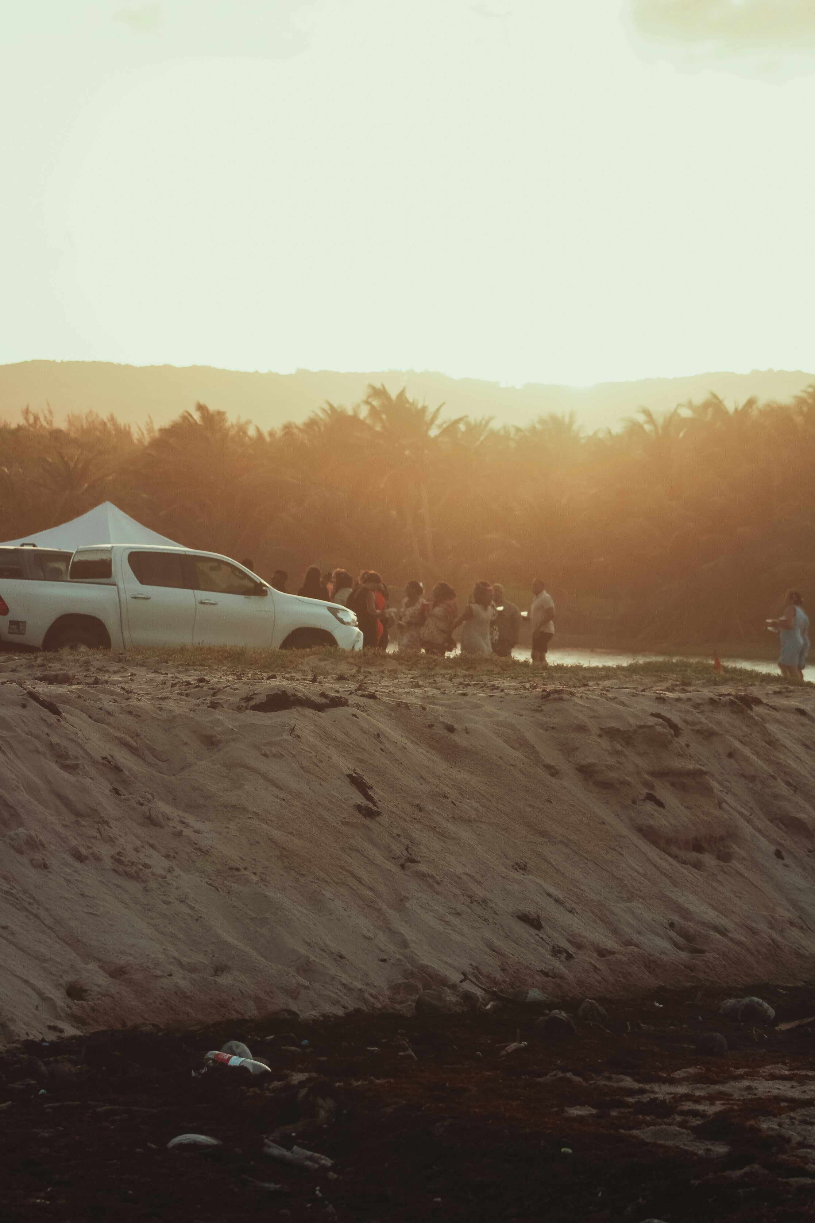 Sunset convoy: silhouettes and a white pickup at the riverbank