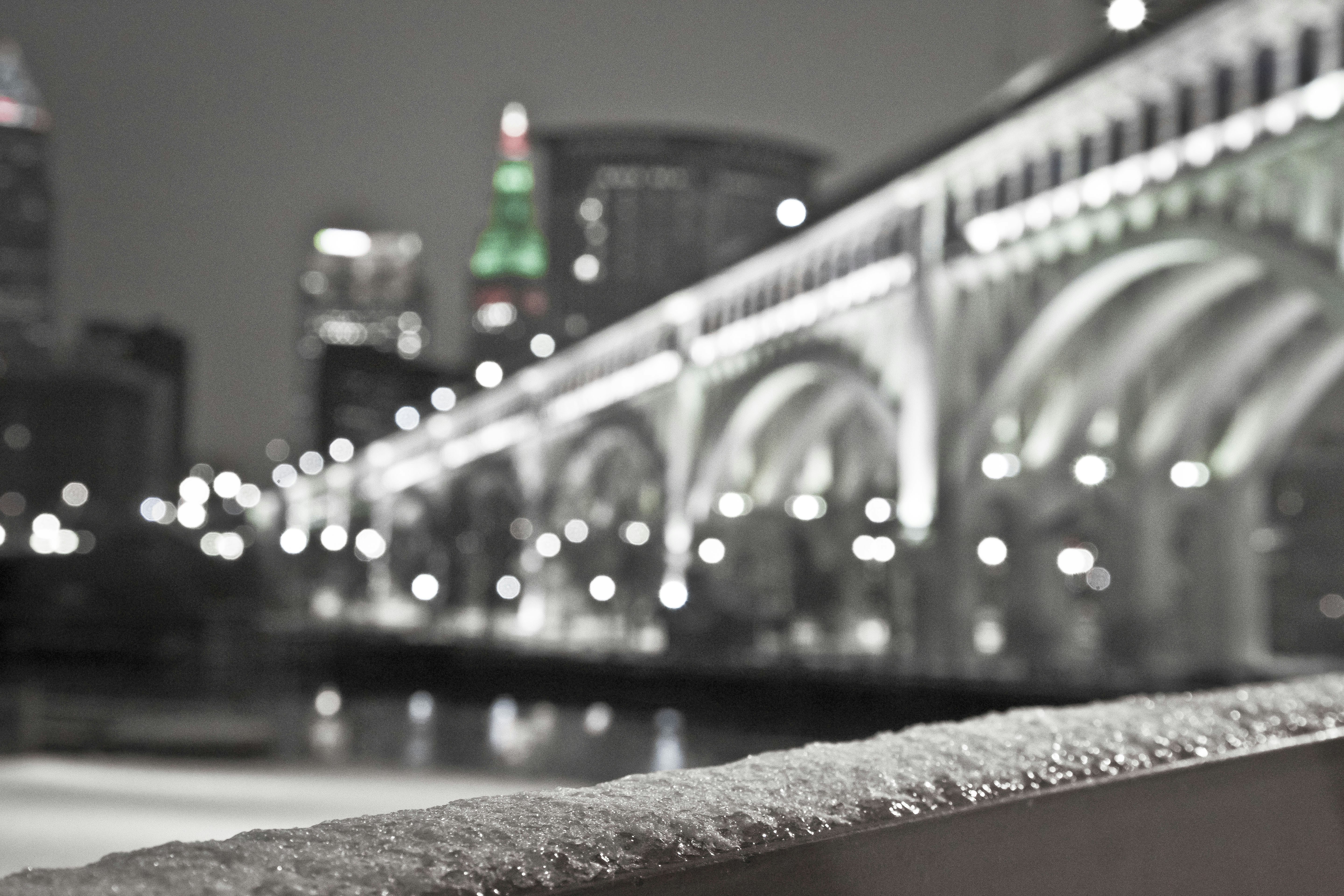 Urban Ribbon of Light: Snowy Railings and Arched Bridge at Night