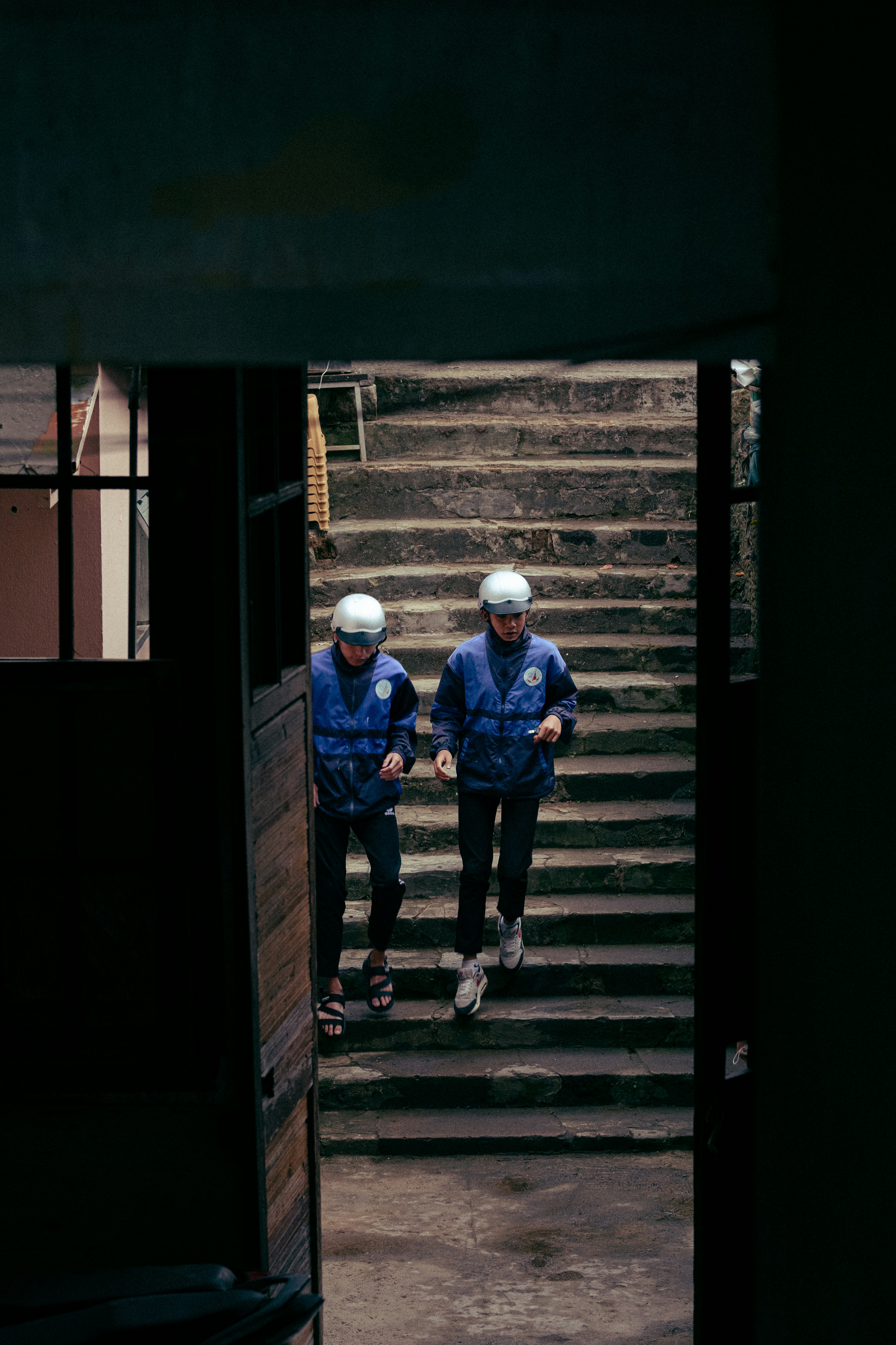 Two uniformed rescuers descend a dim stairway into daylight