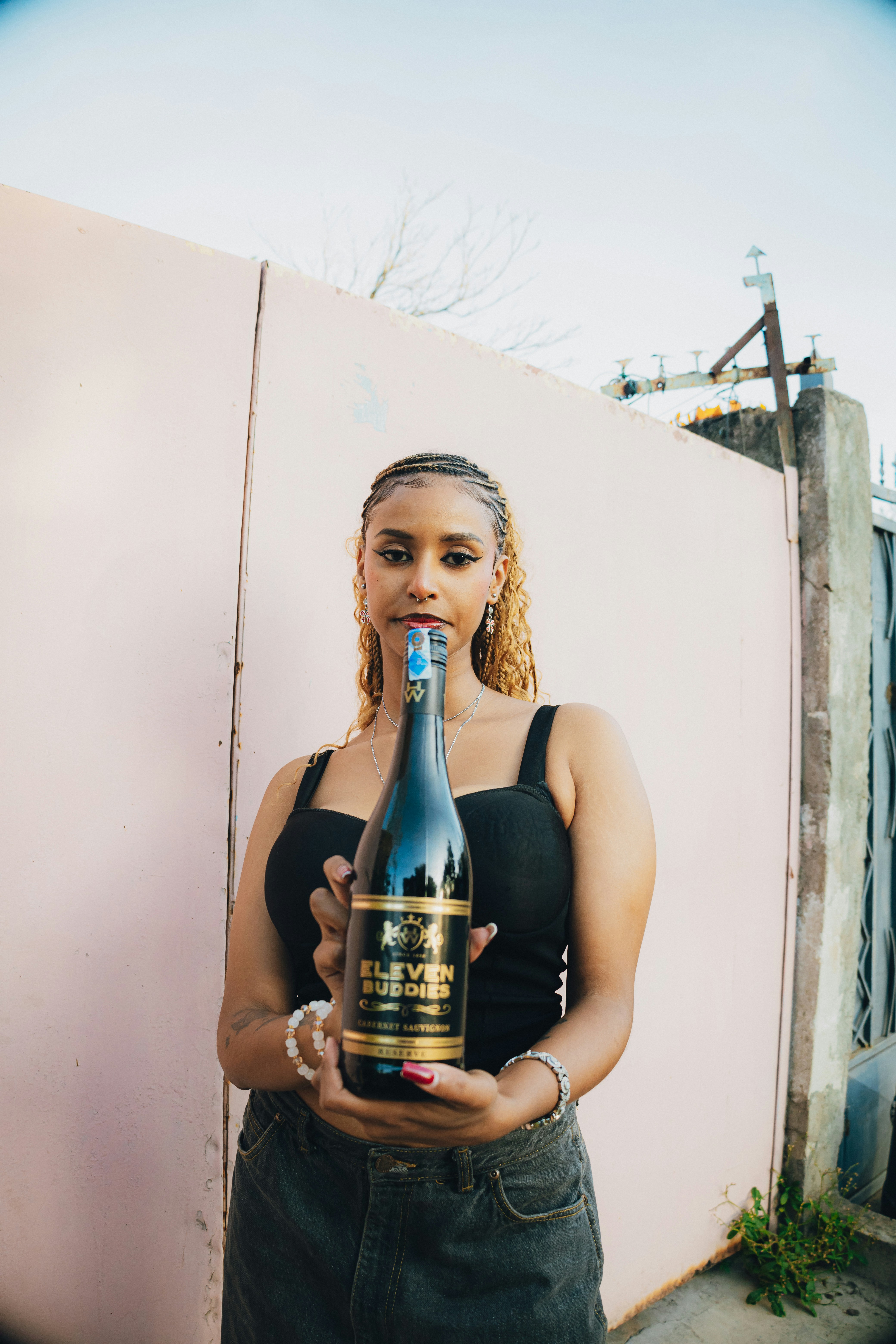 Bottle Portrait: A confident gaze with a celebratory bottle in front of a pastel wall
