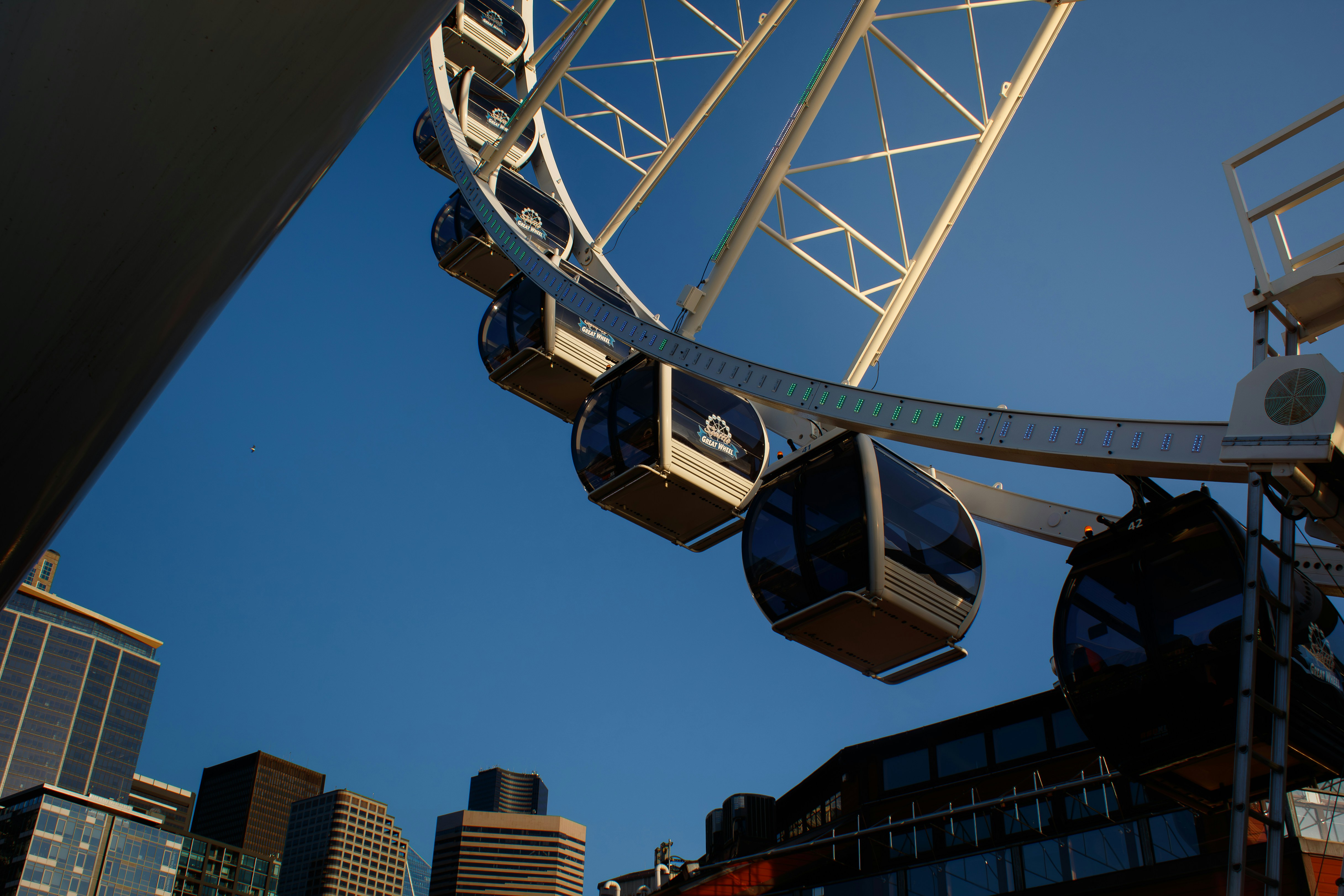 Aerial Carriage in the Sky: Urban Ferris Wheel Against a Clear Blue Horizon