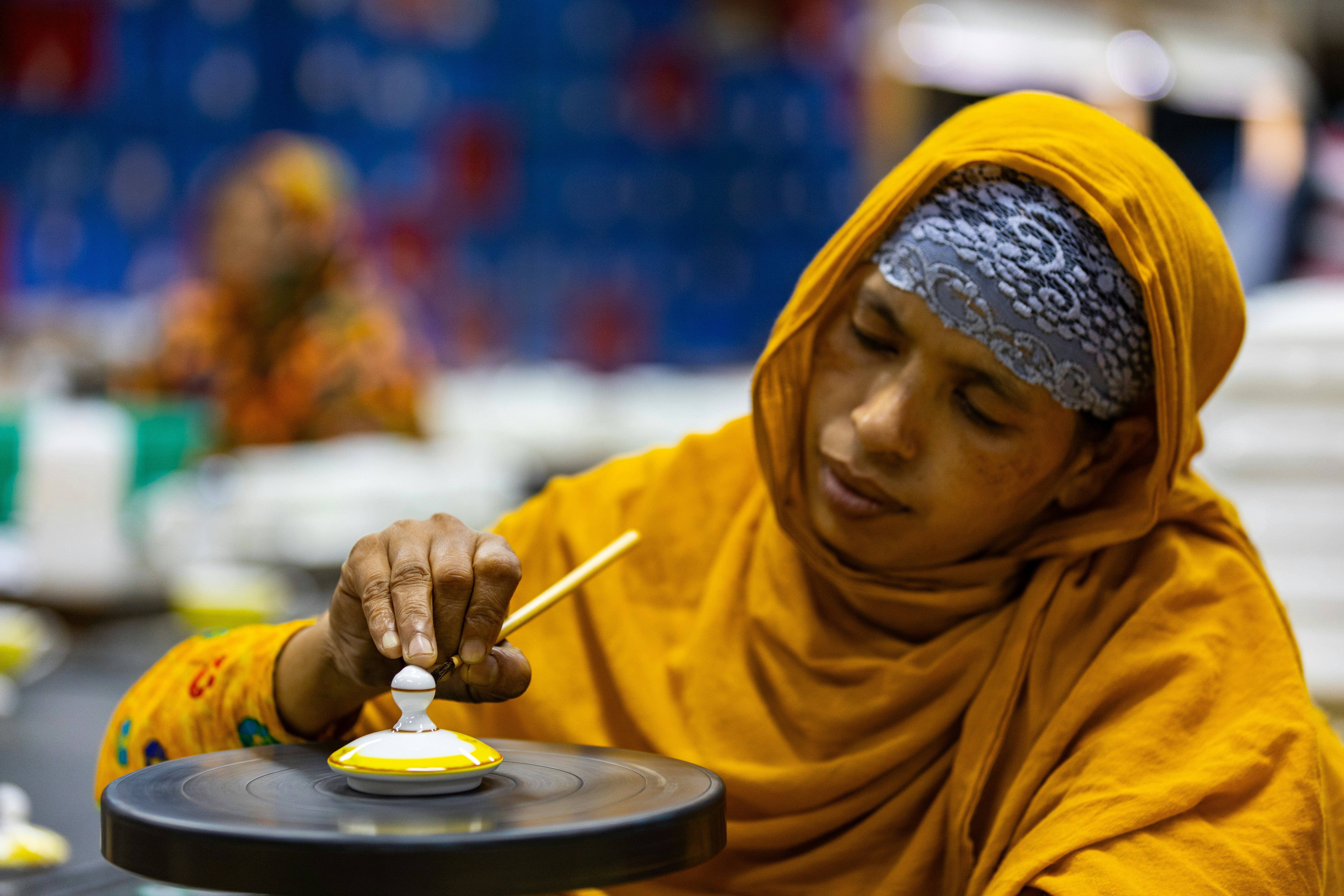 Golden Hour Pottery: A Woman in Orange Concentrates on a Pottery Wheel