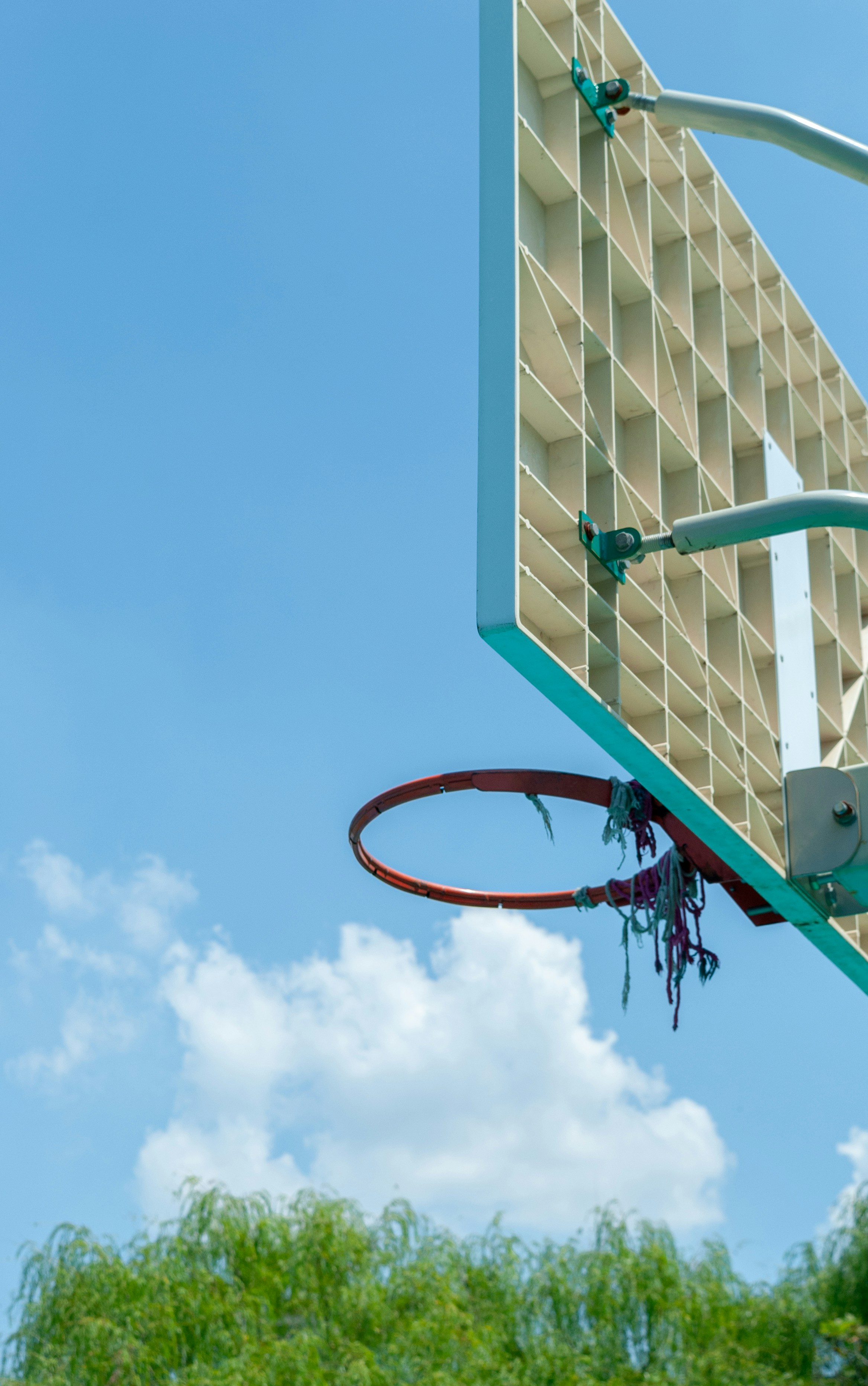 Low-Angle View of a Weathered Basketball Backboard Against a Bright Sky